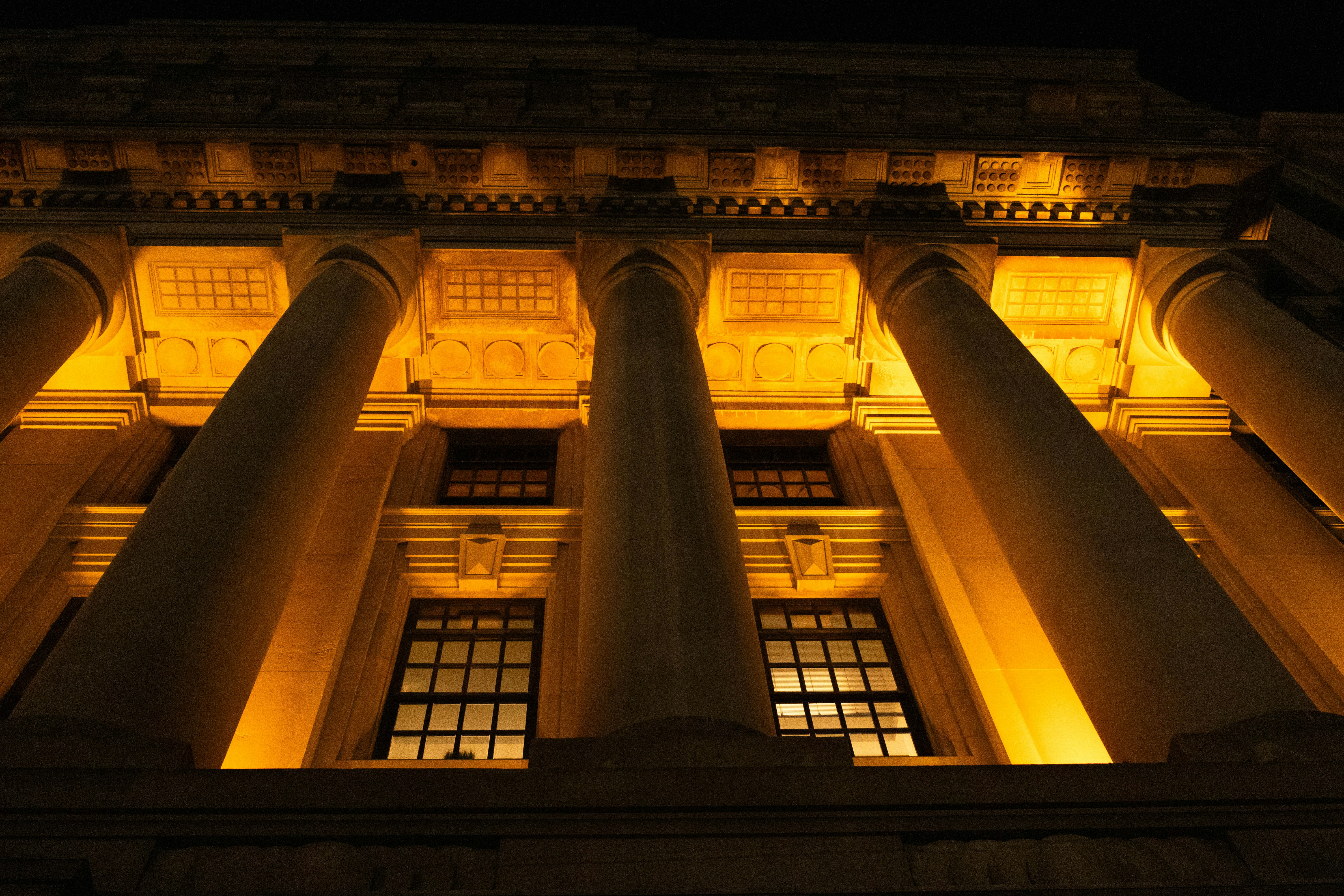 Majestic columns illuminated by warm light, showcasing intricate architectural details against a night sky.