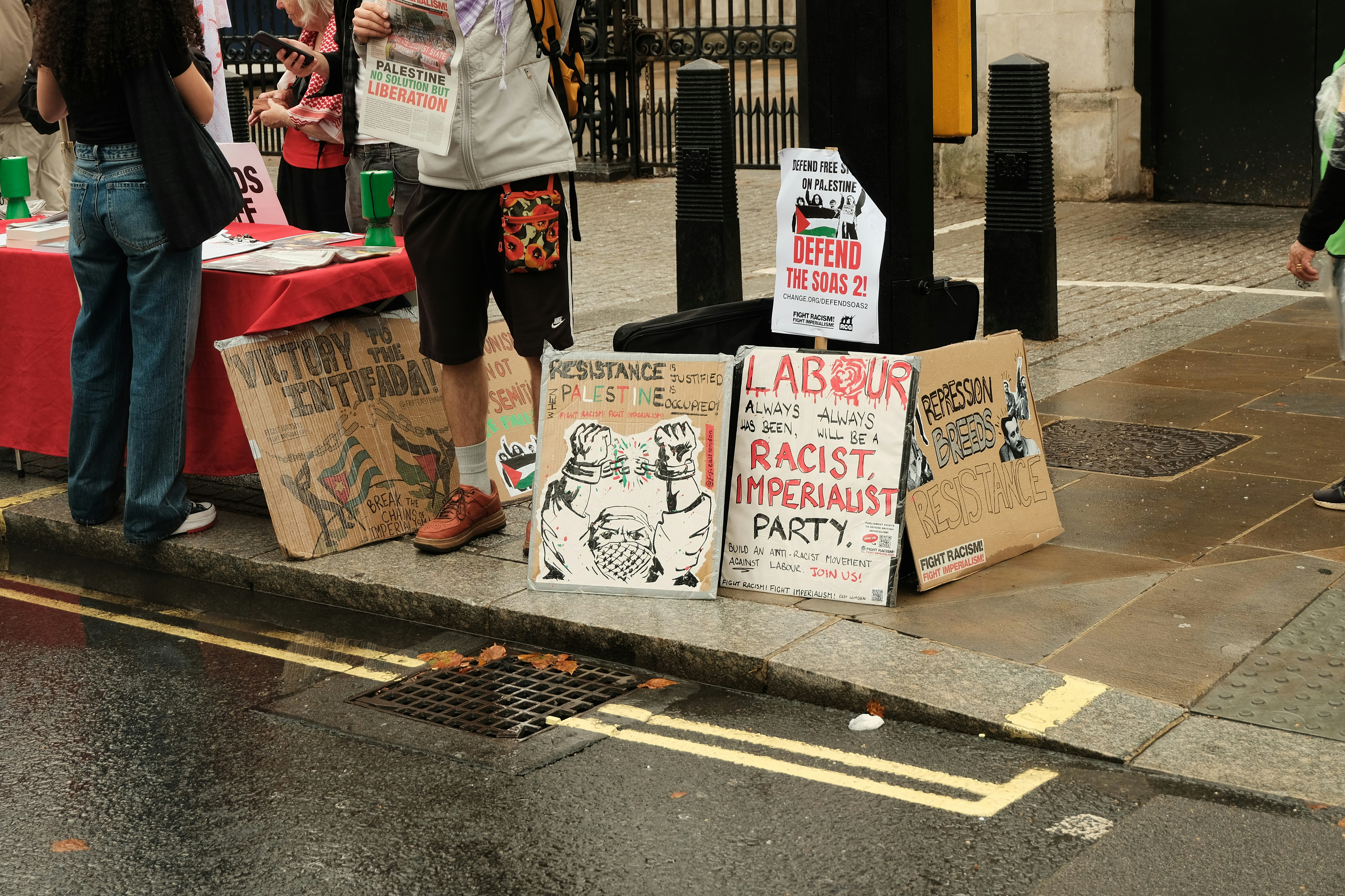 Protest signs and people on a wet city street.