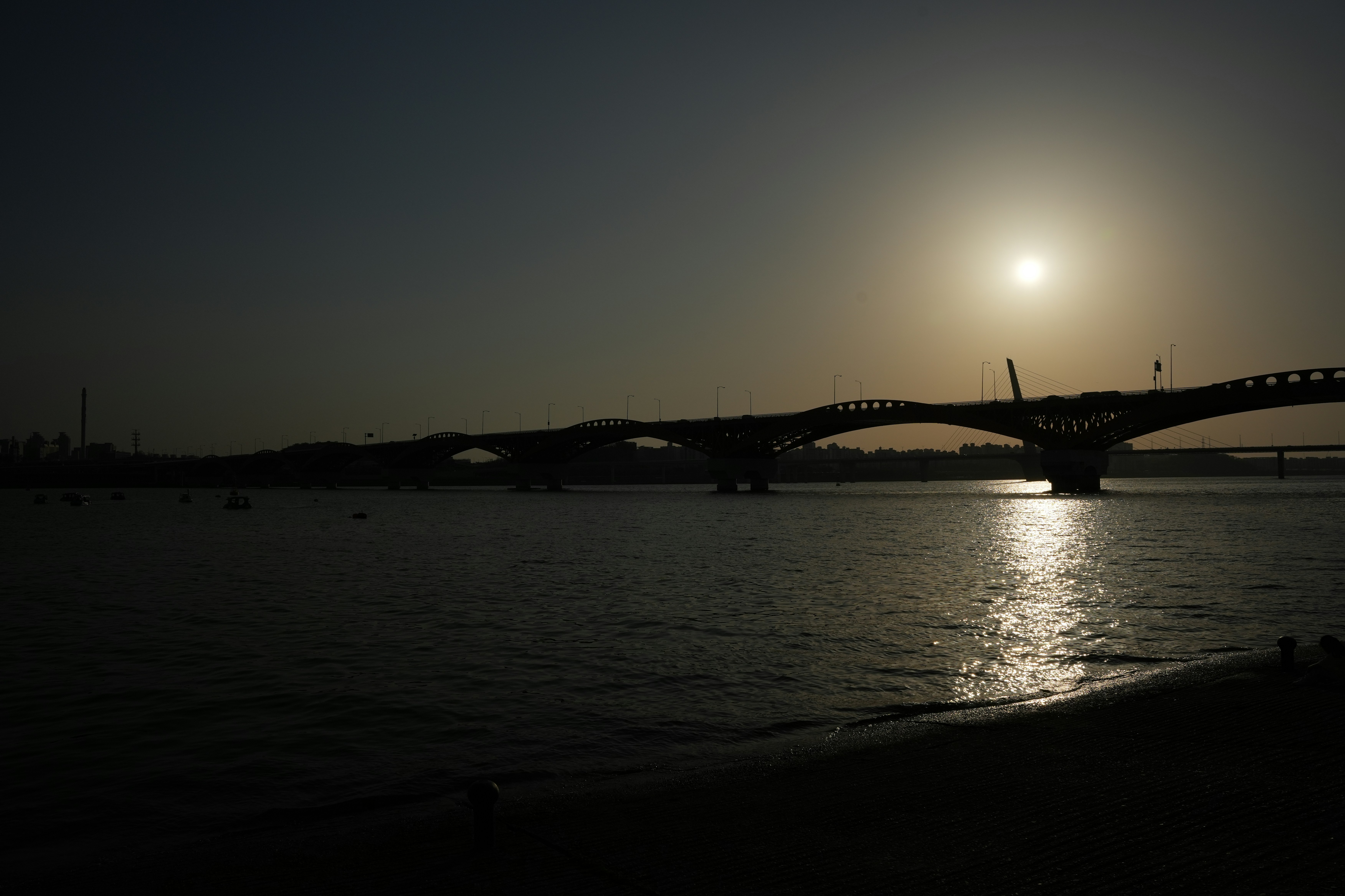 Dusk Over the Arched Bridge: A Sunlit Silhouette Across the River