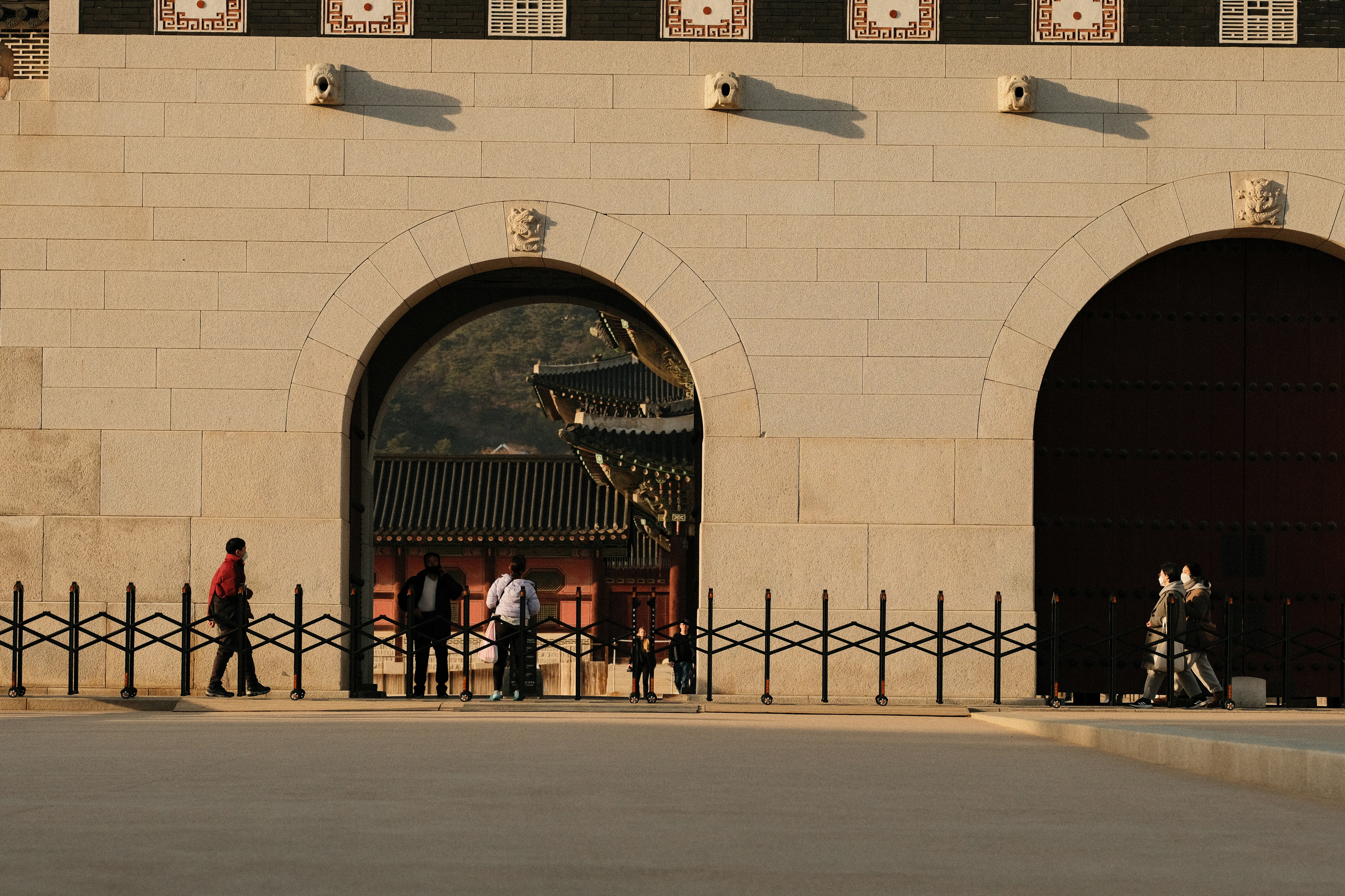 People walk near arched entrances of a building.