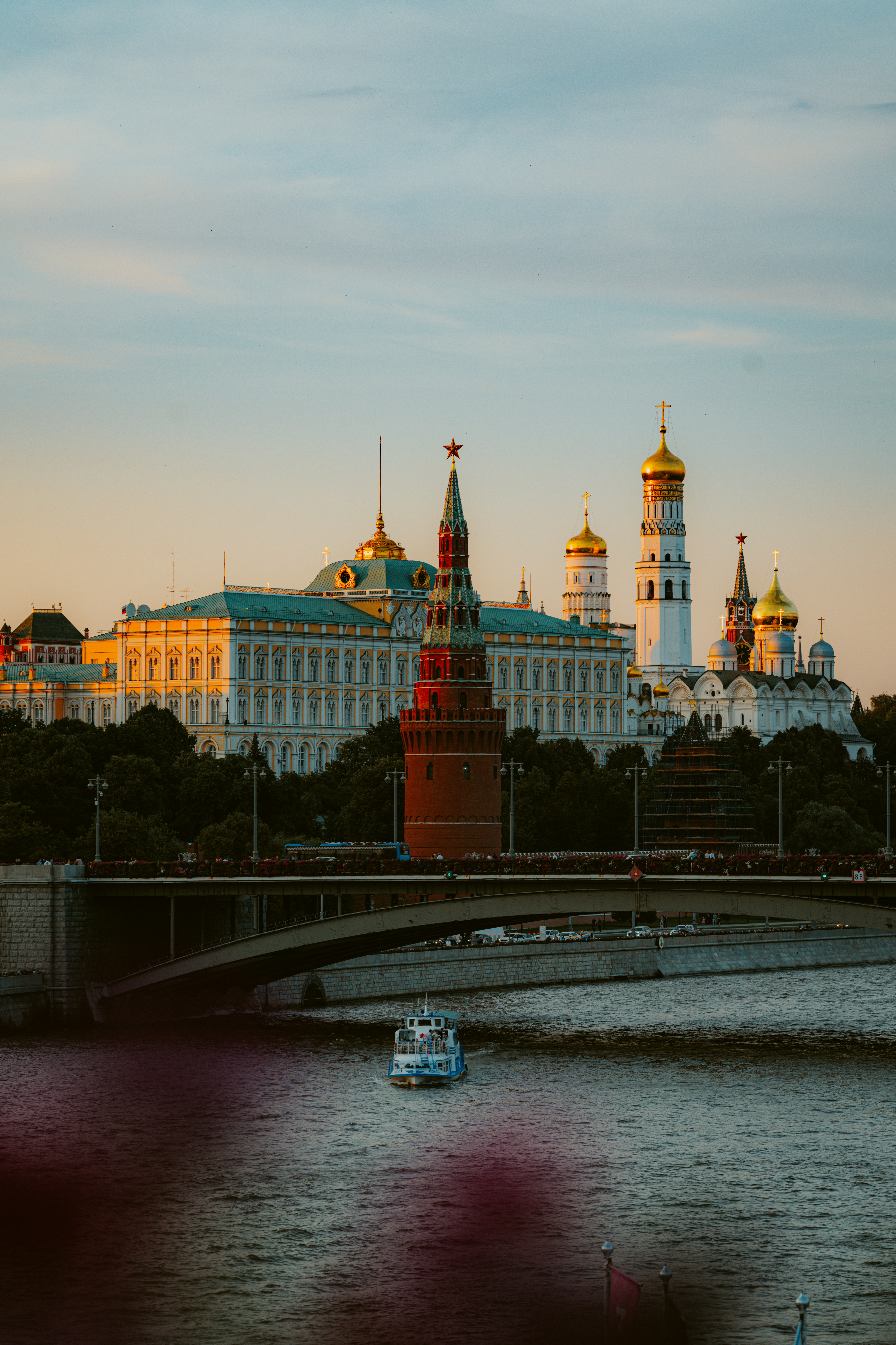 The iconic Kremlin towers and golden domes of Moscow bathed in soft twilight hues, reflecting on the river below.