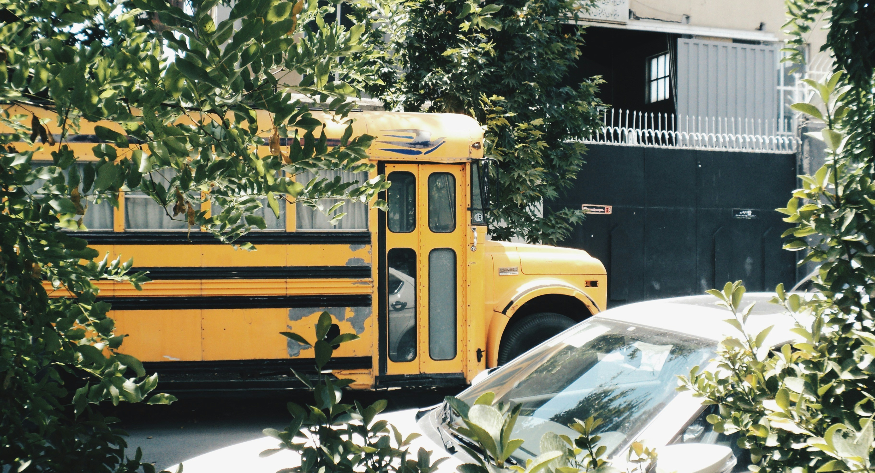 The last stop. | A yellow school bus is parked near a car.