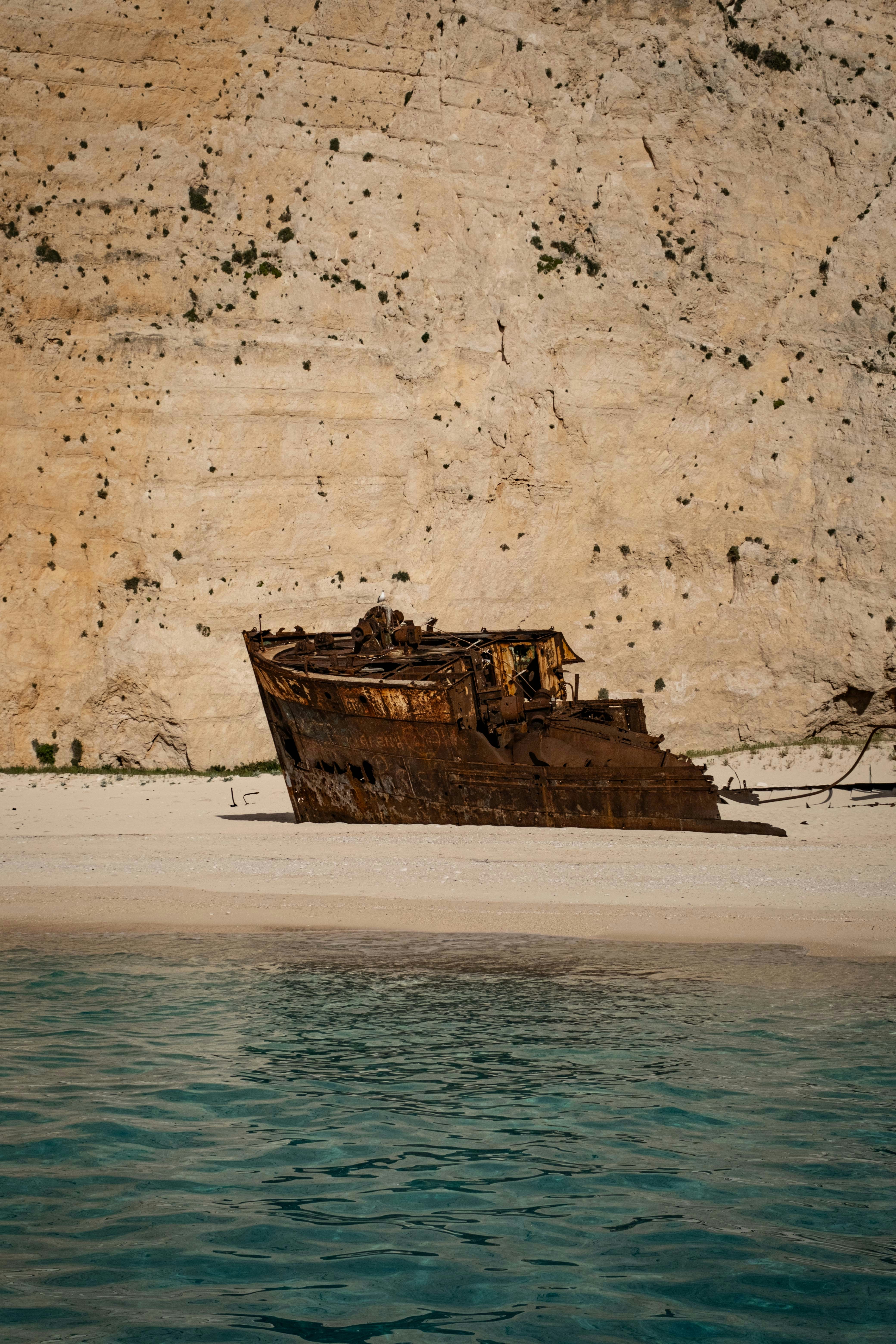 Rust-Scarred Hull Beside a Limestone Cliff: Echoes of a Forgotten Shore