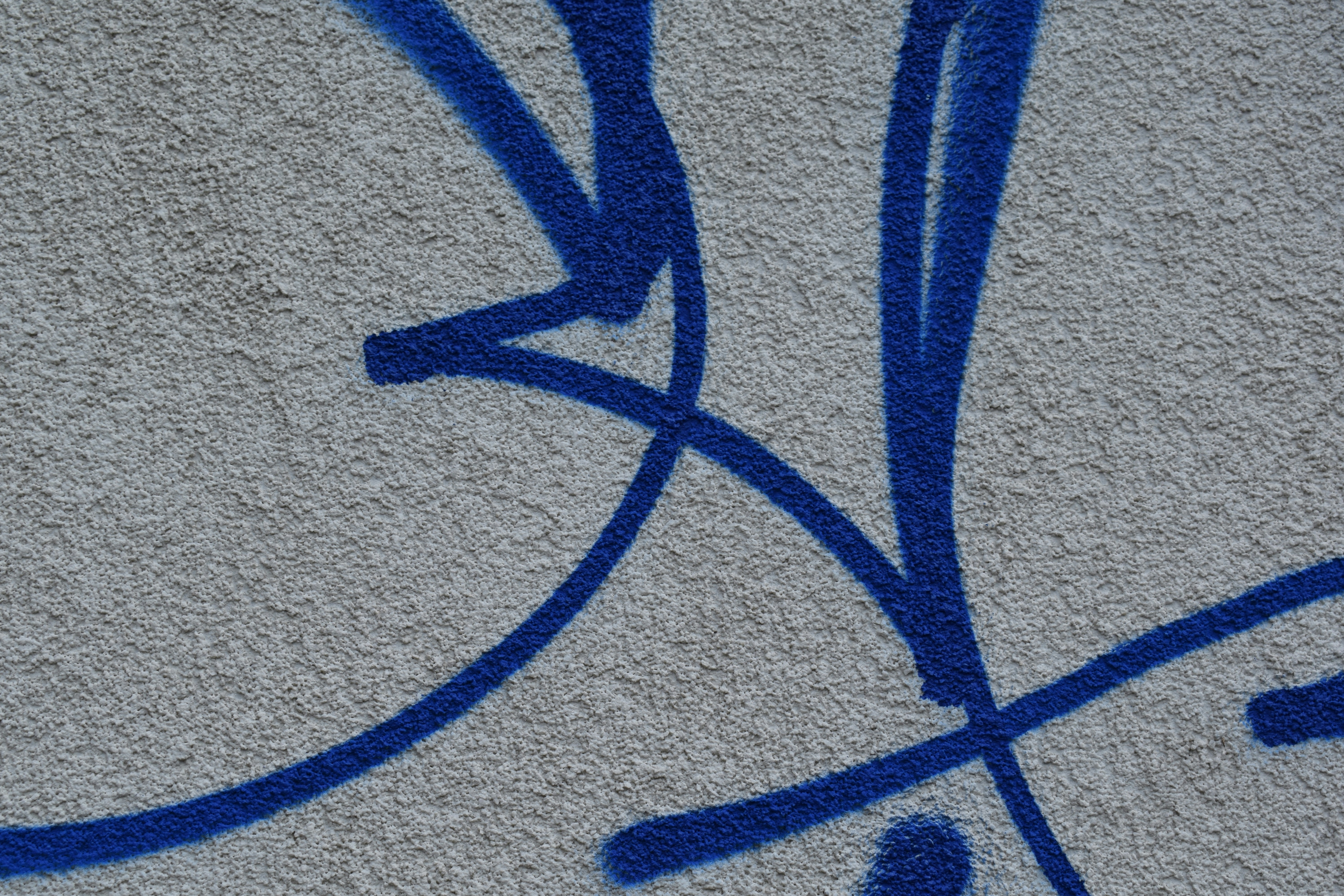 Blue graffiti sprayed on a textured surface.