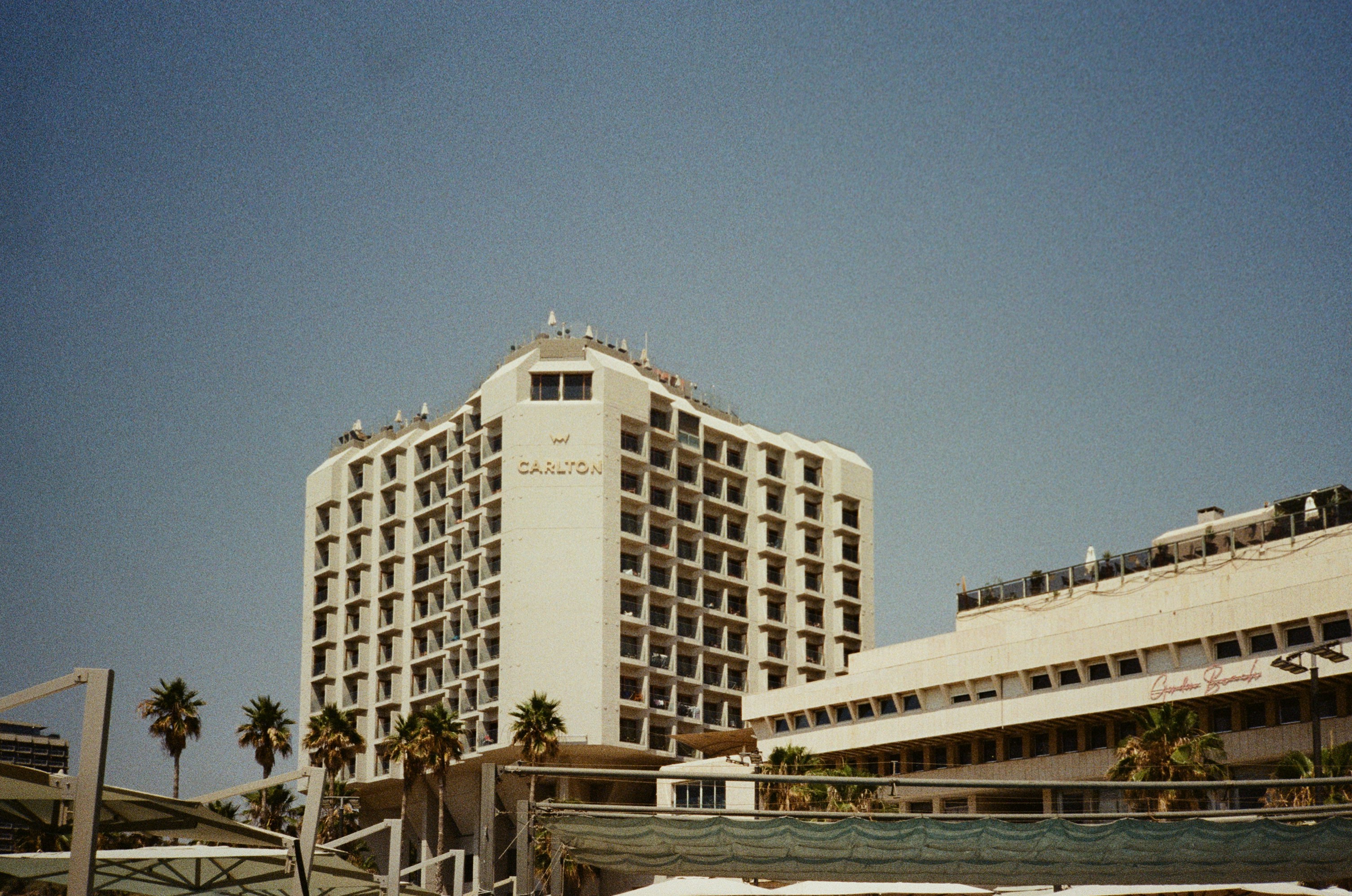 A tall white hotel stands under a blue sky.