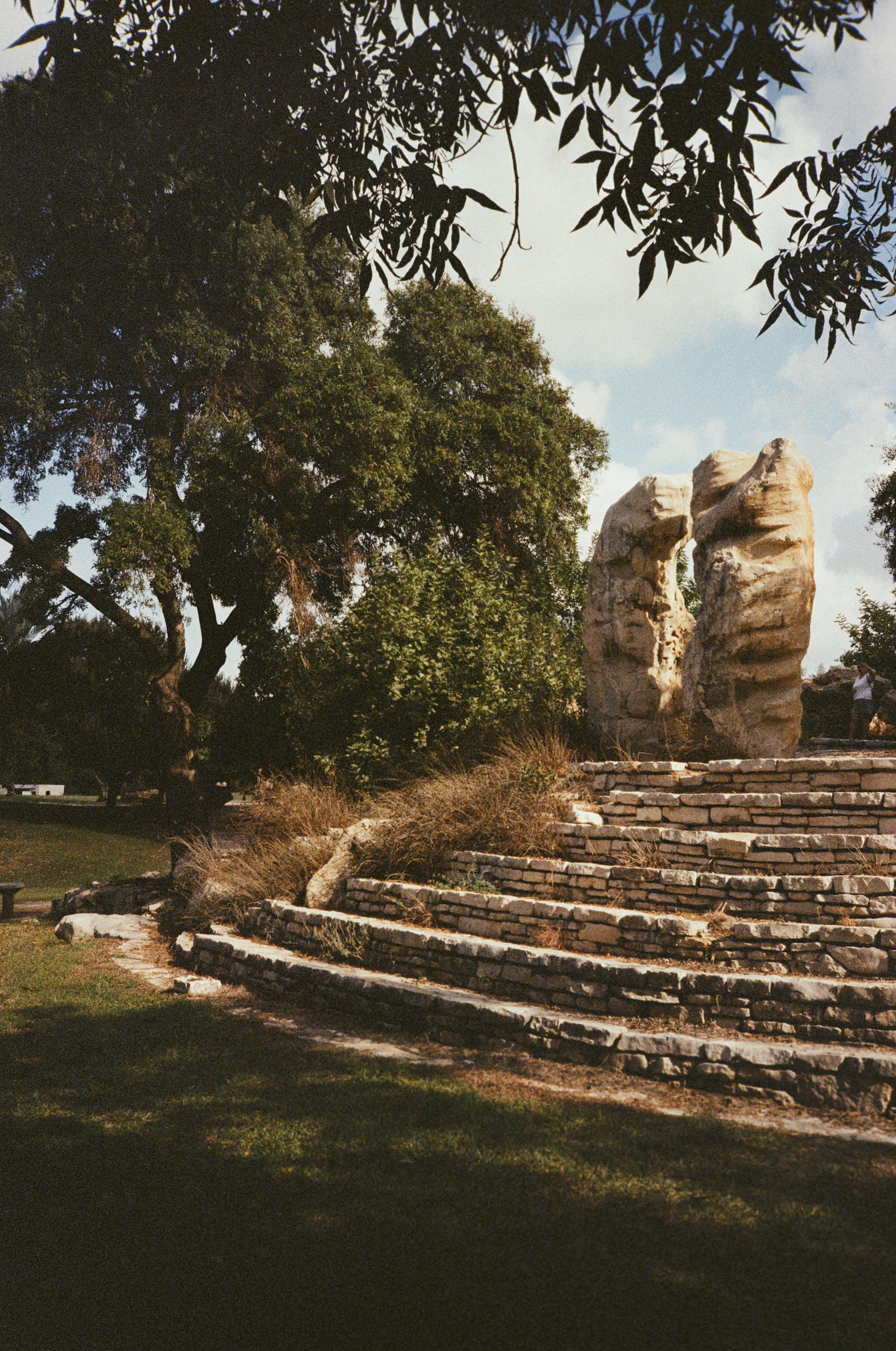 Stone steps lead to a sculpture in a park.