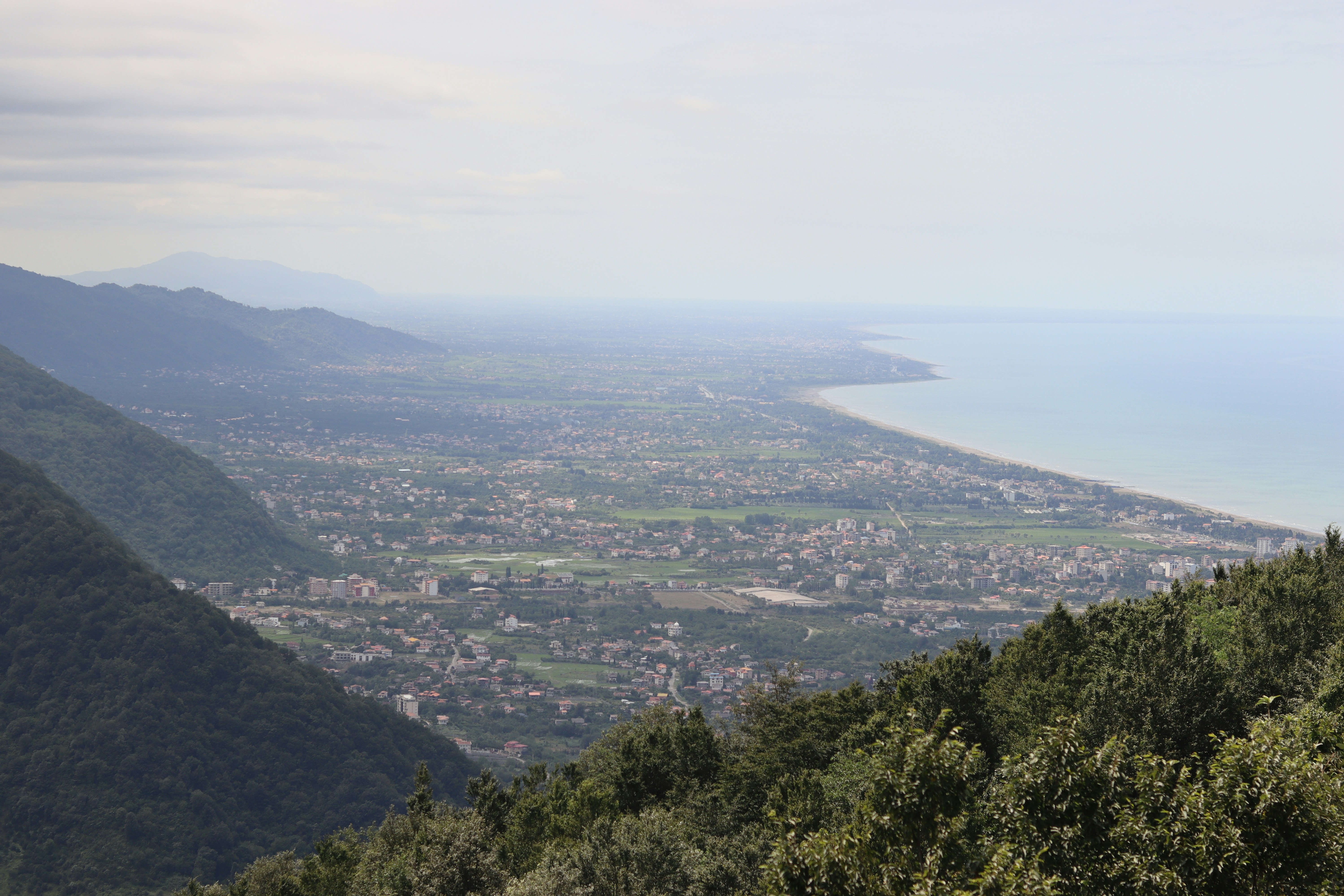 A sprawling town meets the sea under a hazy sky.