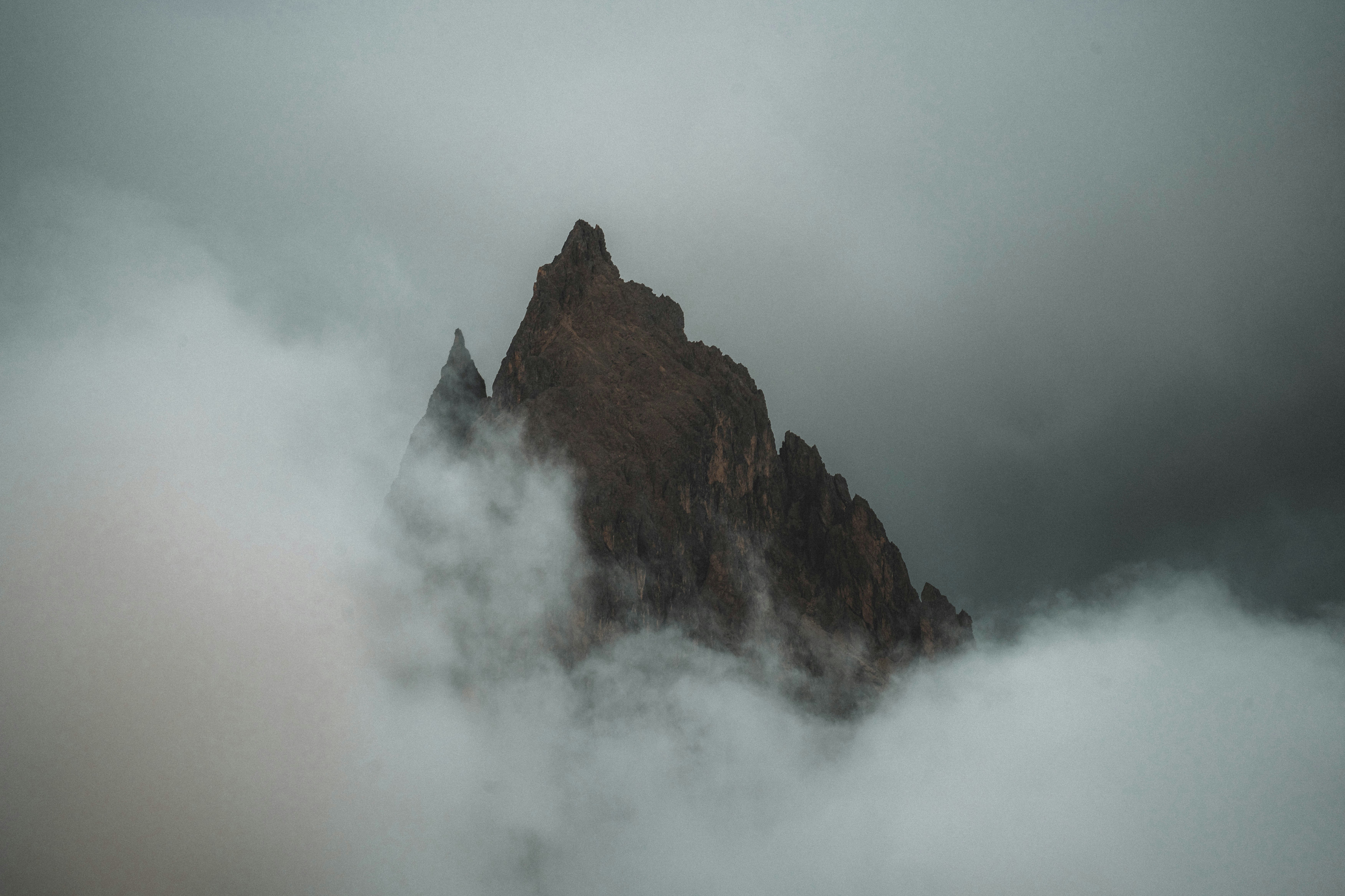 A misty mountain peak emerges from the clouds.