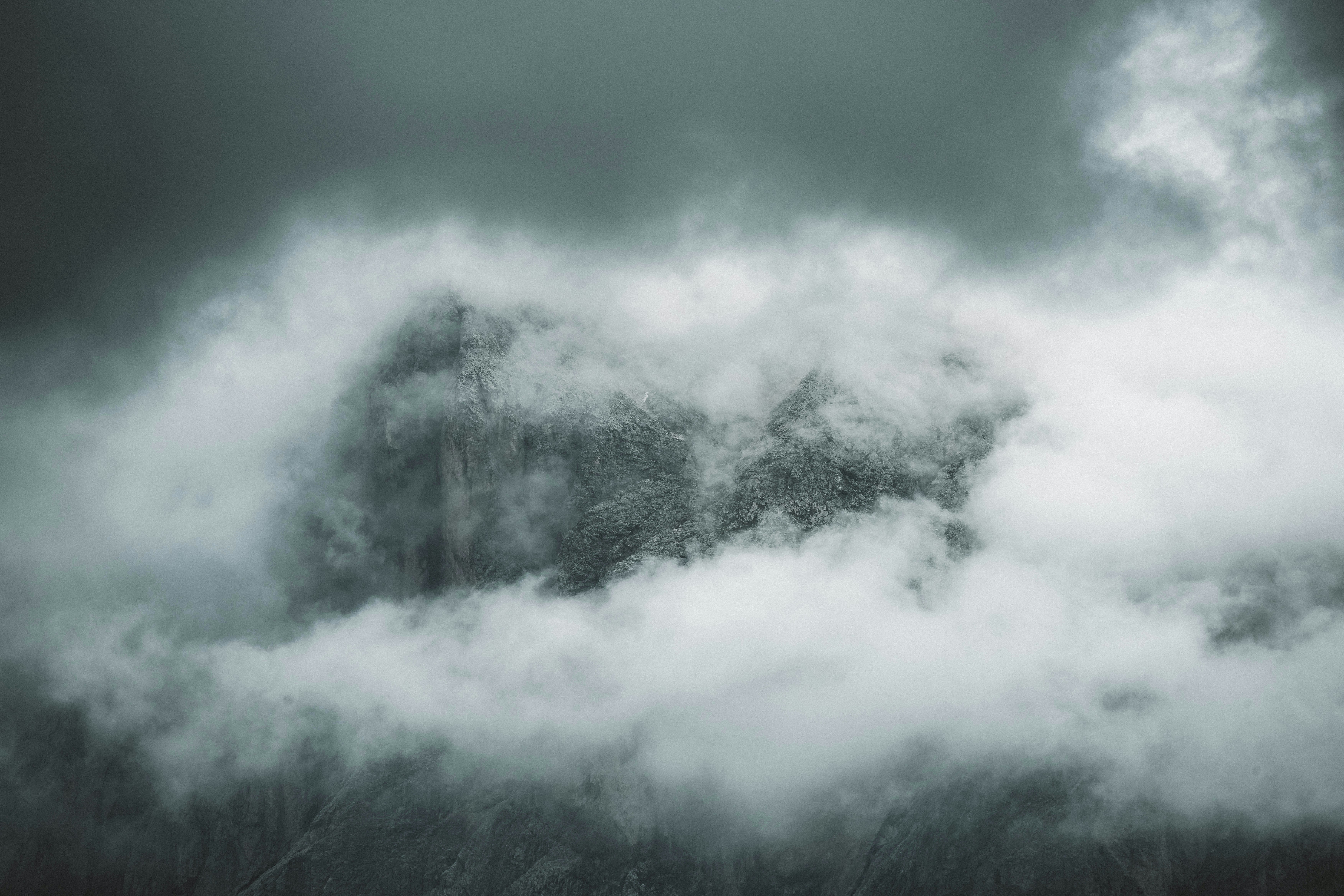 Mountains are enveloped in dense, swirling clouds.