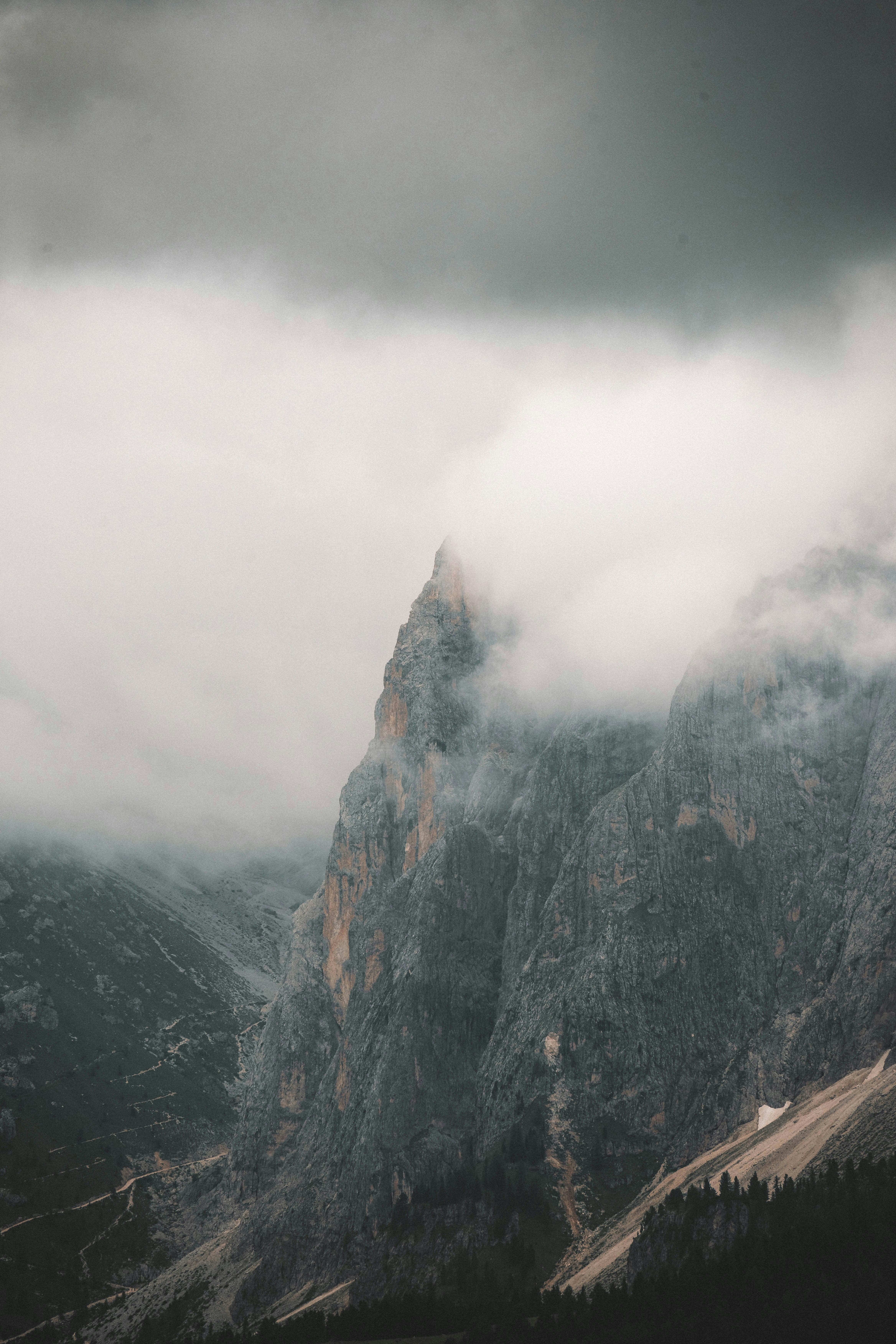 Jagged mountain peak shrouded in mist, surrounded by rugged terrain and dense forests. The atmosphere conveys a sense of mystery and solitude.
