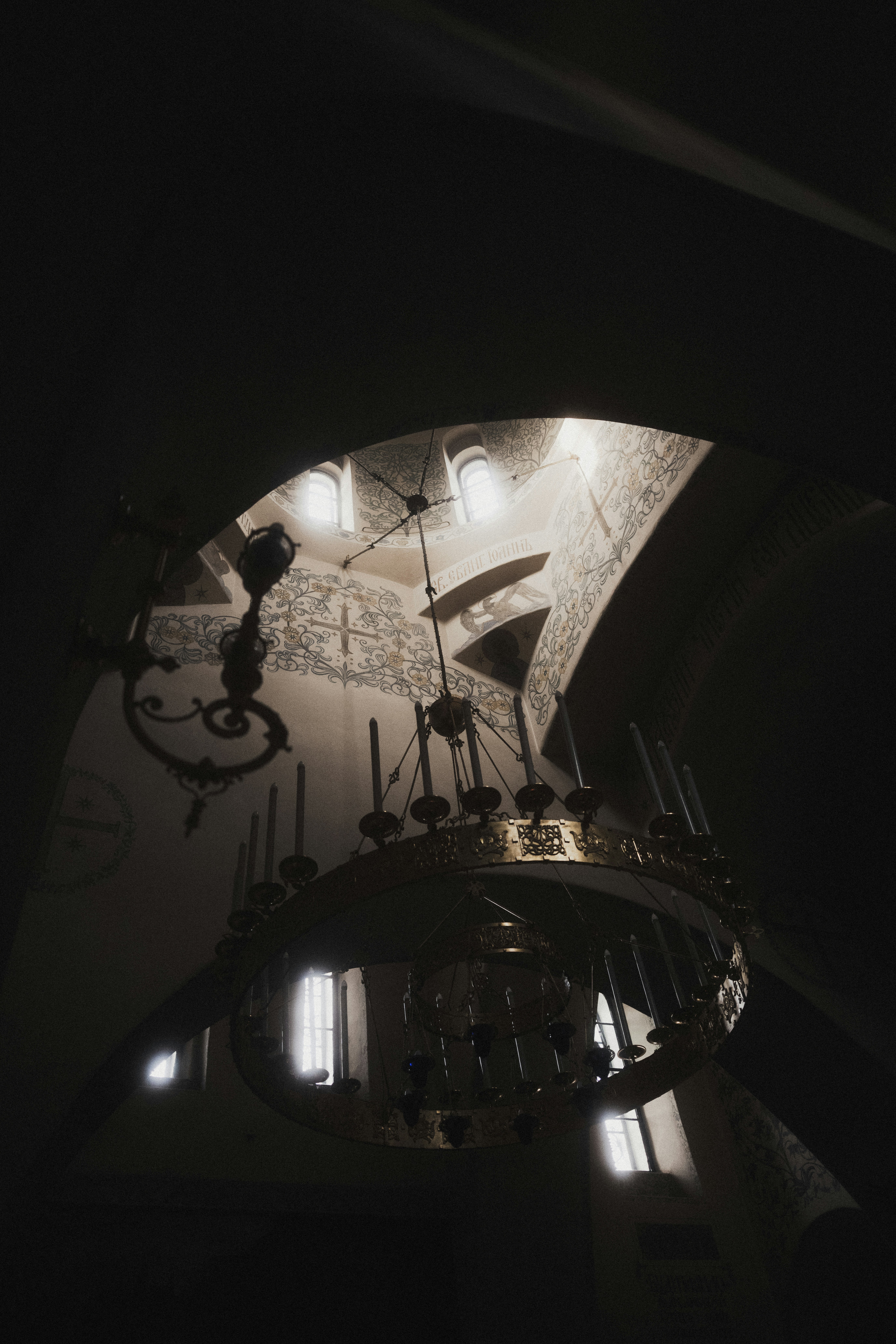 A chandelier hangs in a dimly lit church.