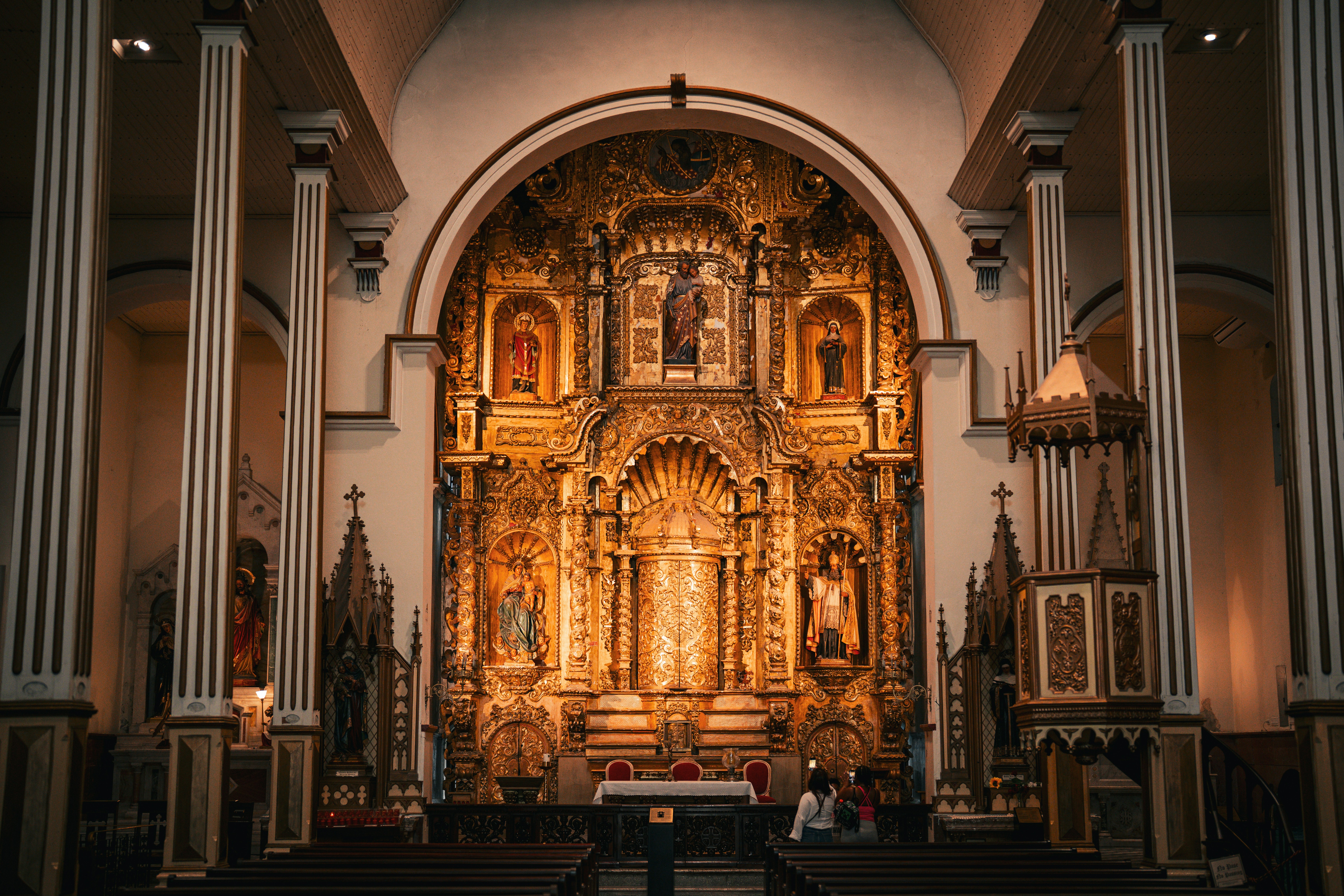 Ornate altar dominates the interior of a grand church.