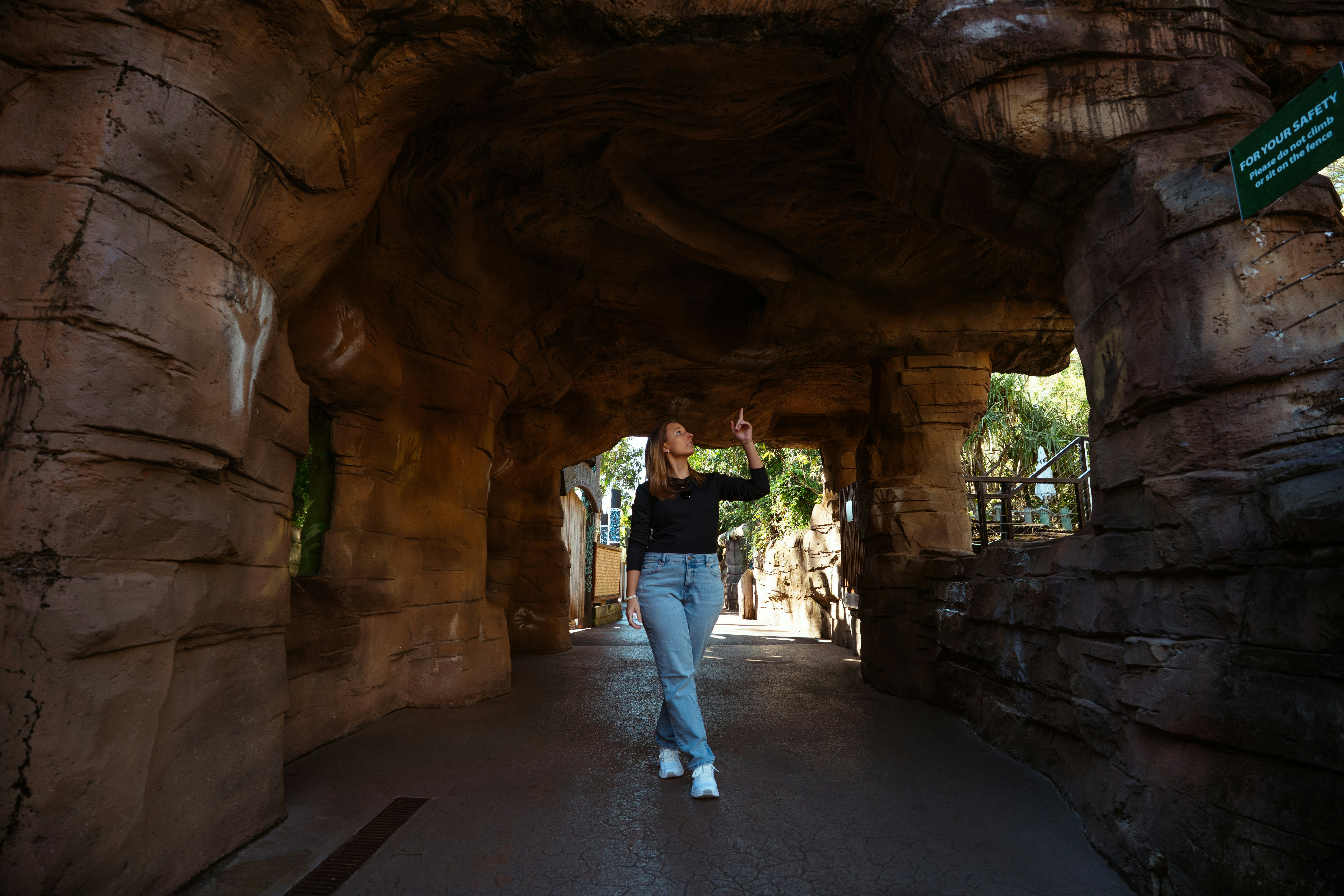 Woman walking through a cave | A woman walks through a rock-like tunnel.