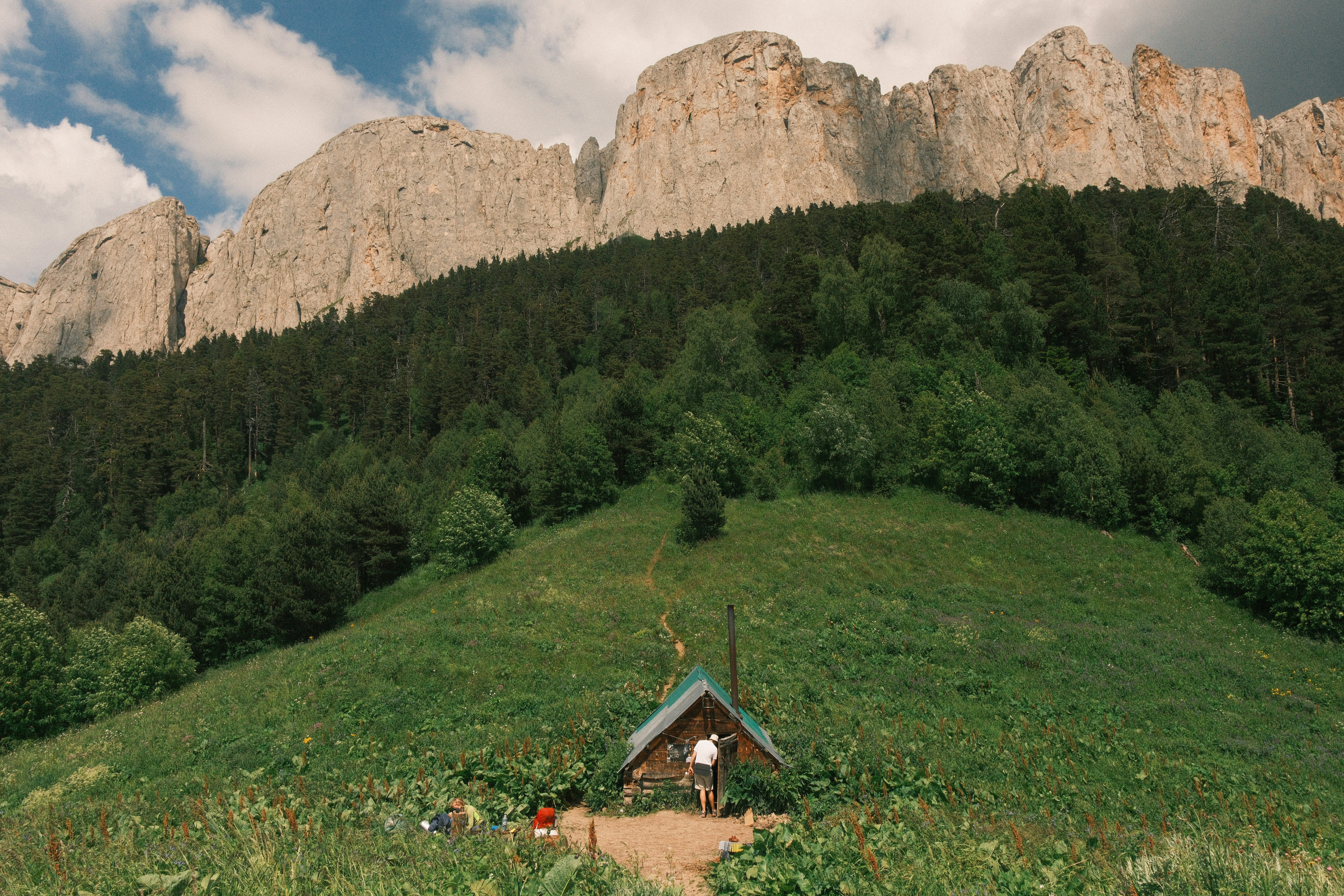 Alpine Shelter at the Foot of Verdant Ridge Beneath Towering Dolomite Cliffs