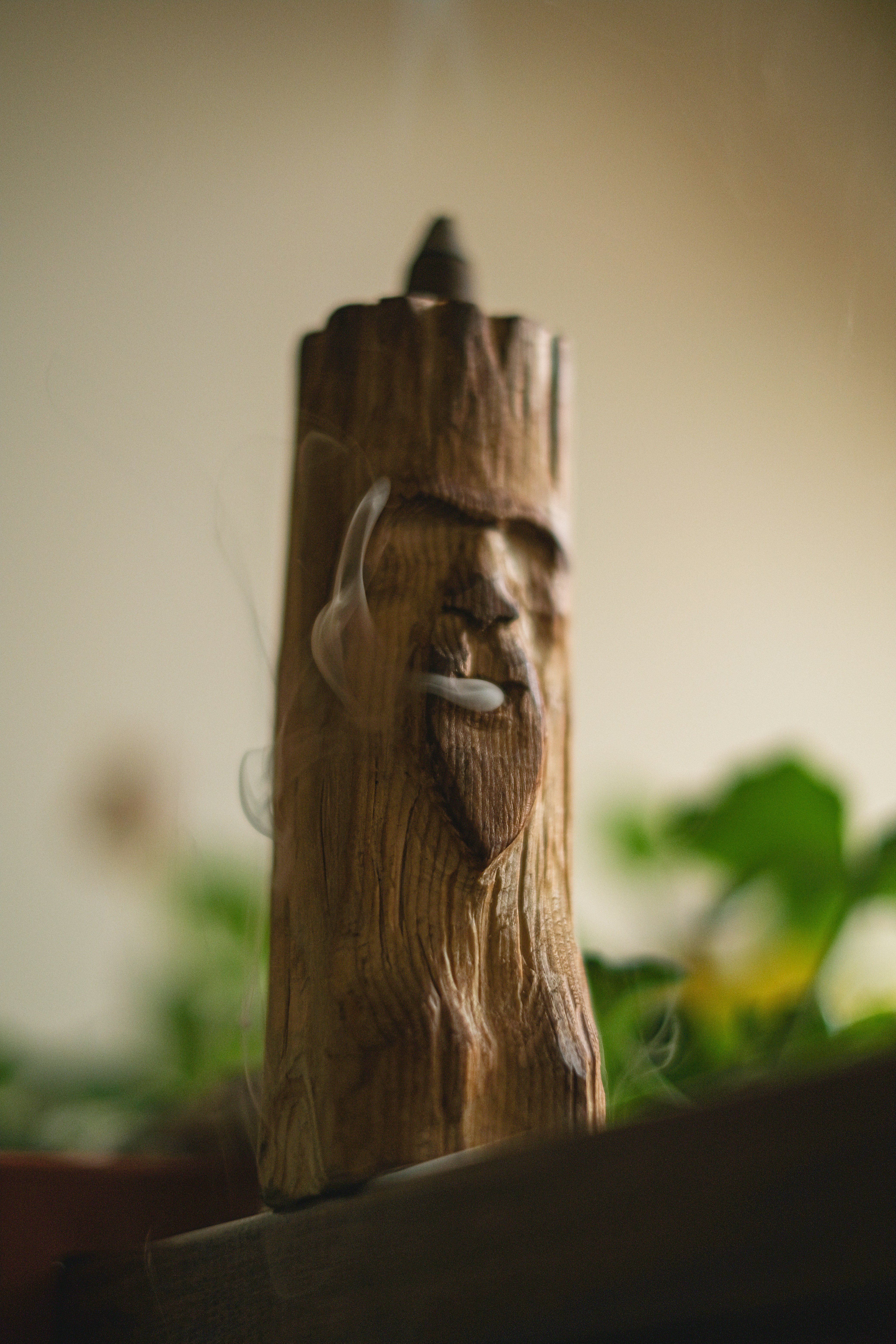 Incense burner with carved face, smoking peacefully.