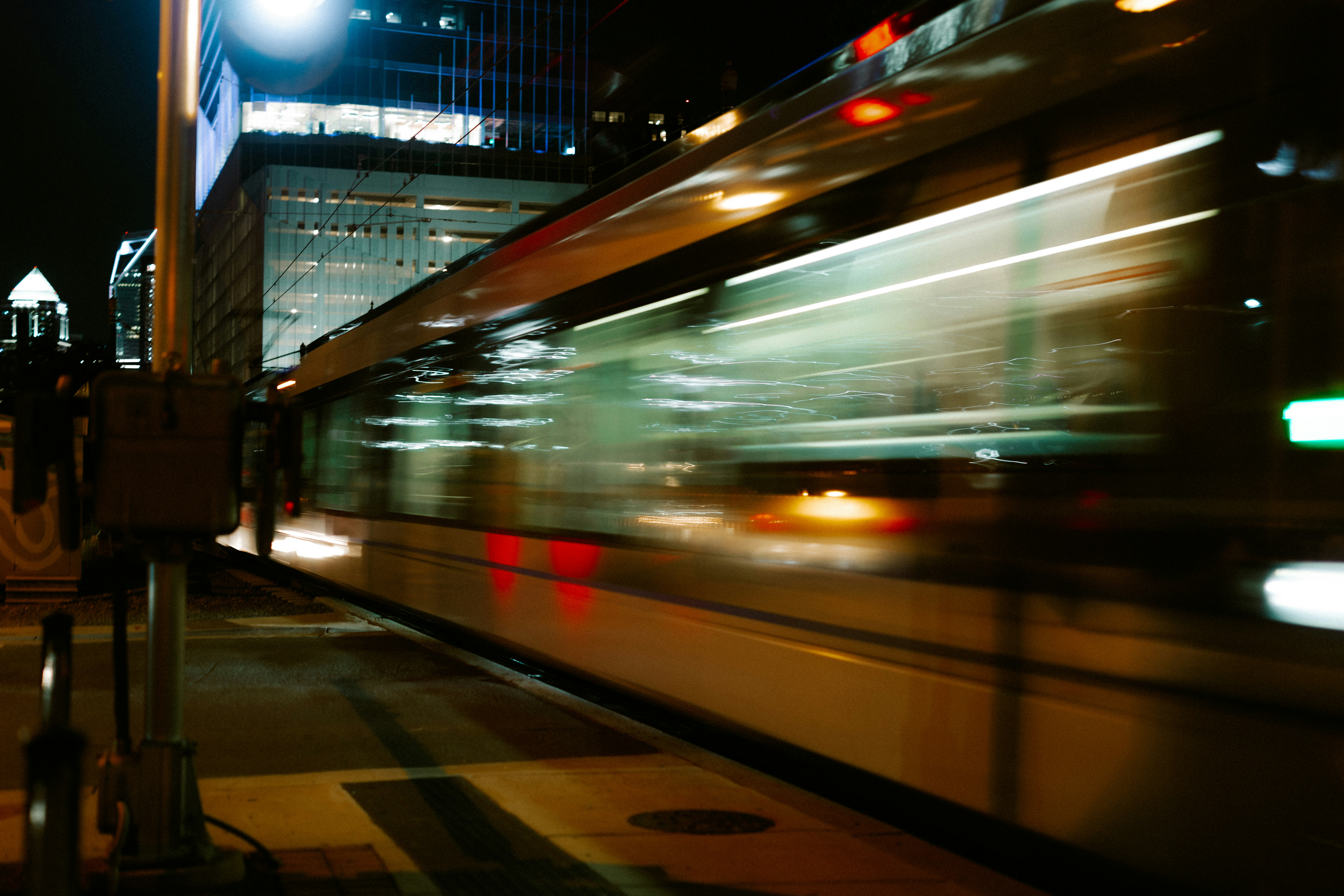 A high-speed train blurs past a cityscape at night, capturing the essence of urban transit. The vibrant lights create a dynamic contrast against the dark surroundings.