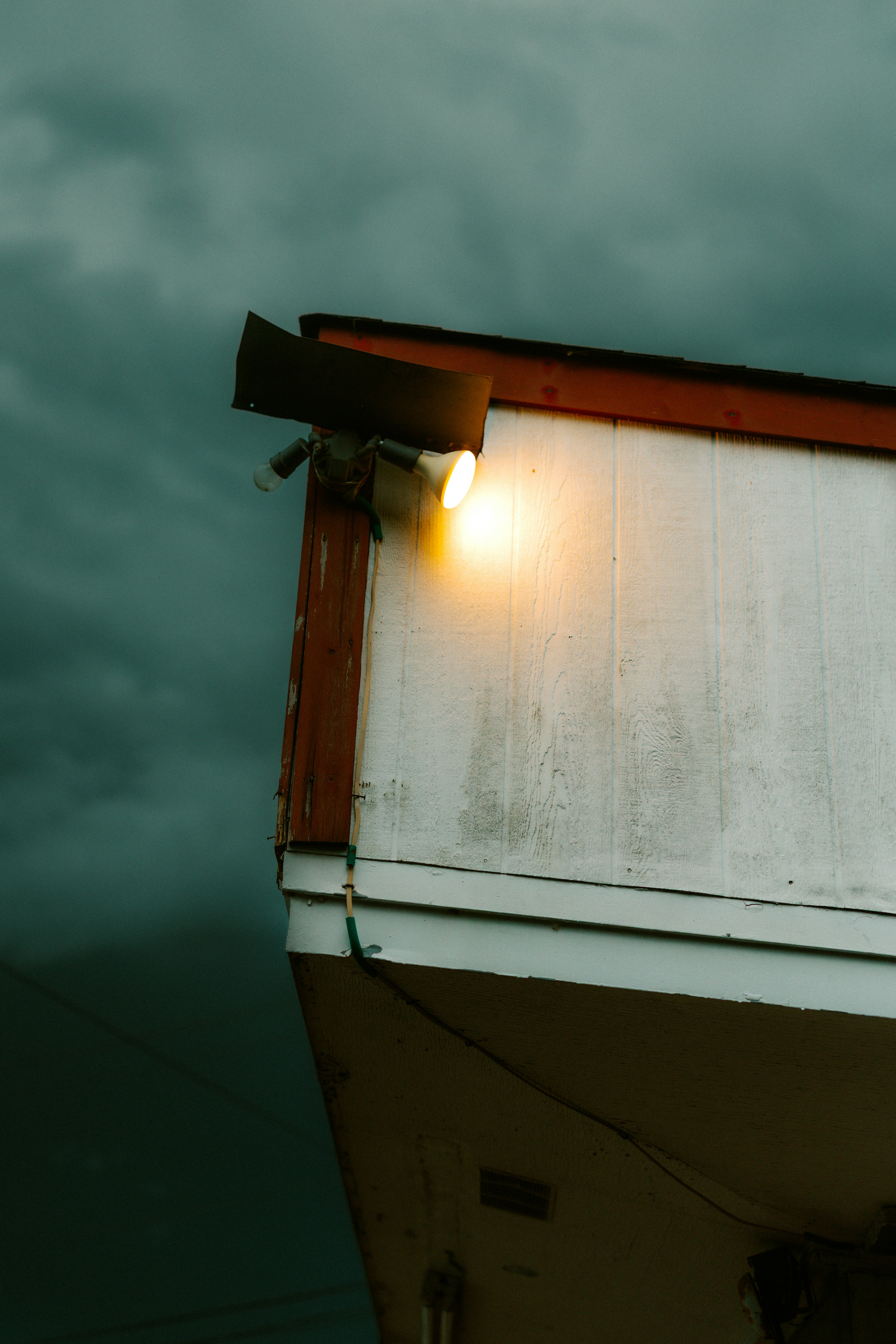 Edge Glow: A Weathered Shed Corner Lit by a Lone Wall Lamp