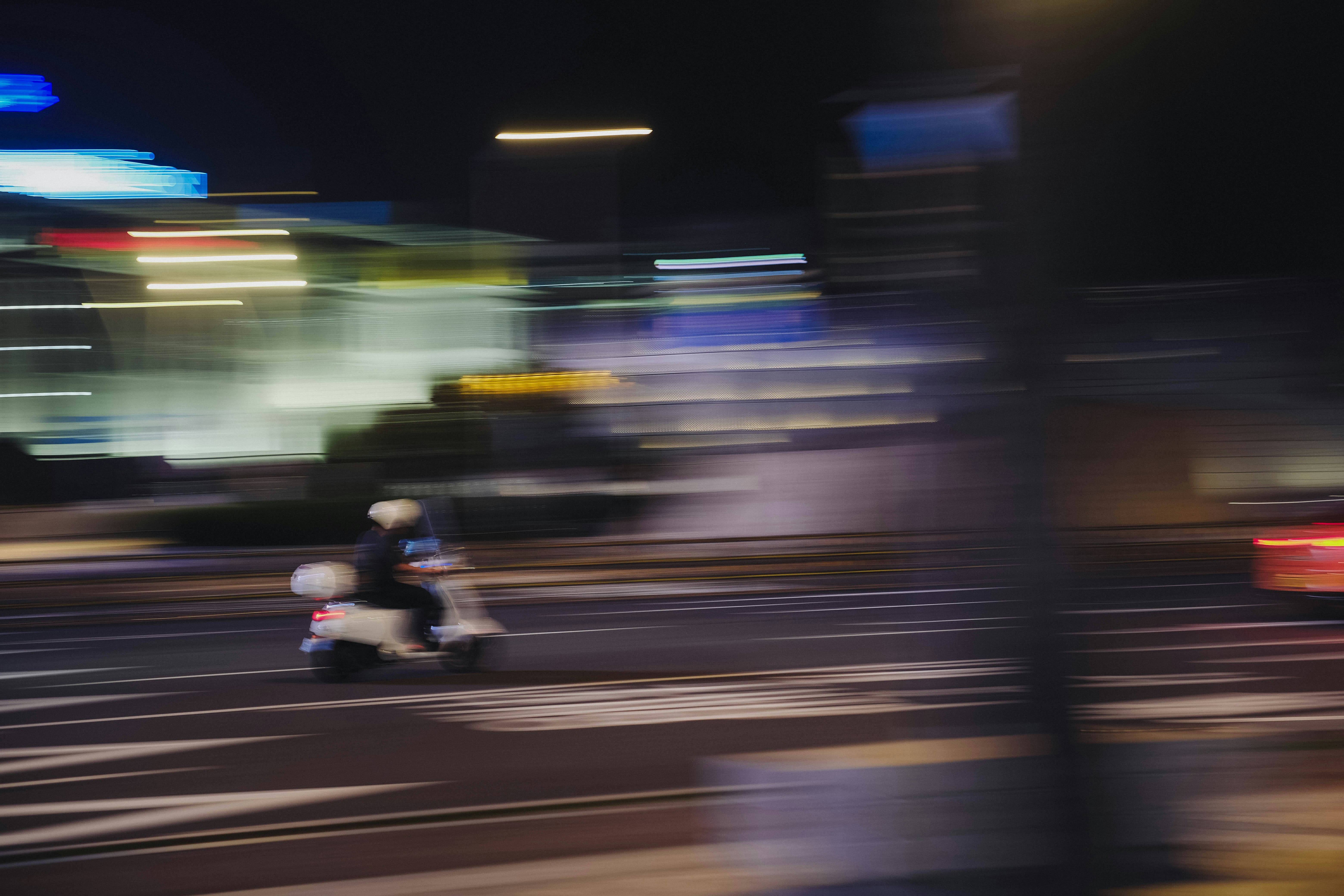 A scooter zips through a city at night.