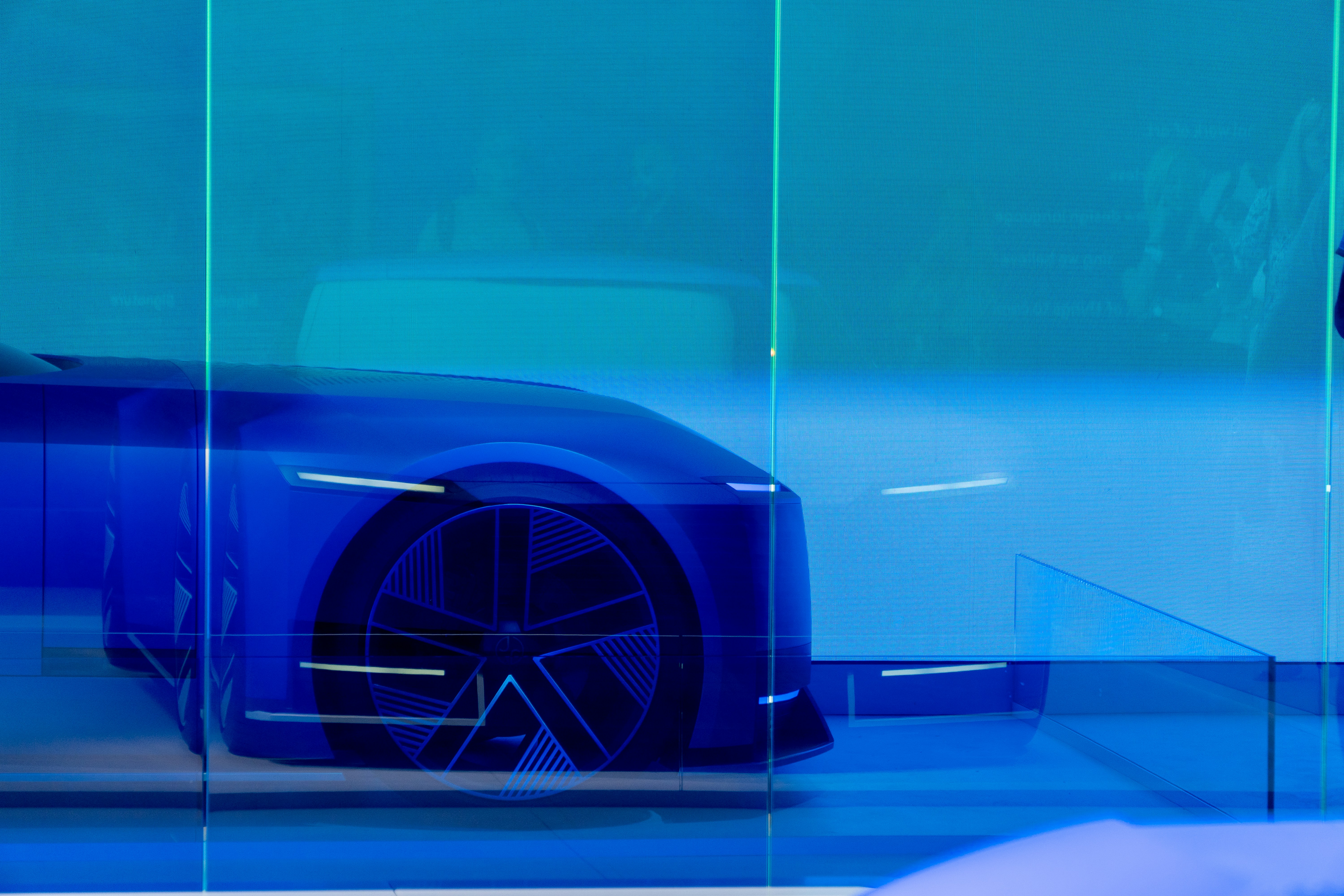 A blue car is seen through glass.