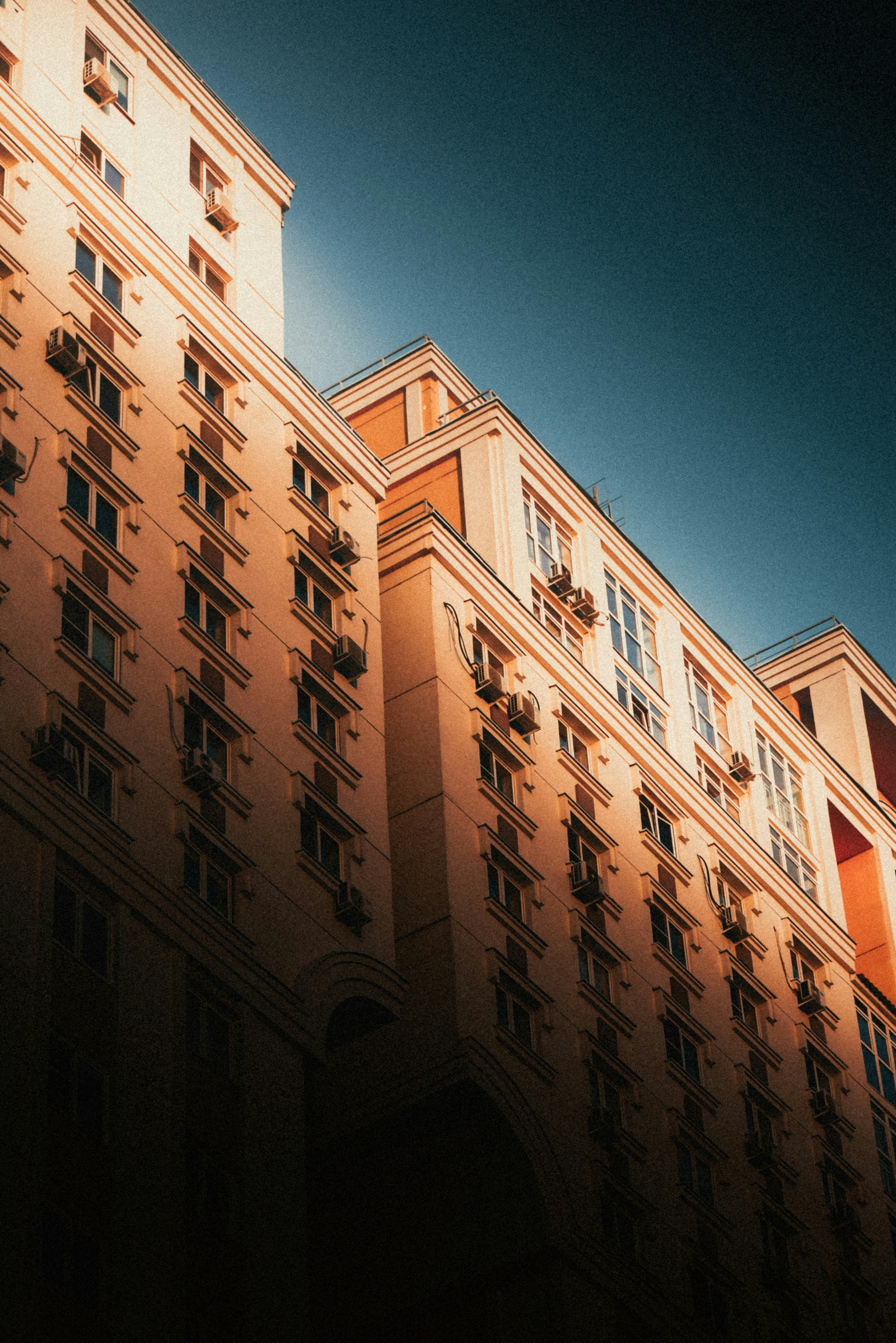 Tall building angles toward a teal sky.