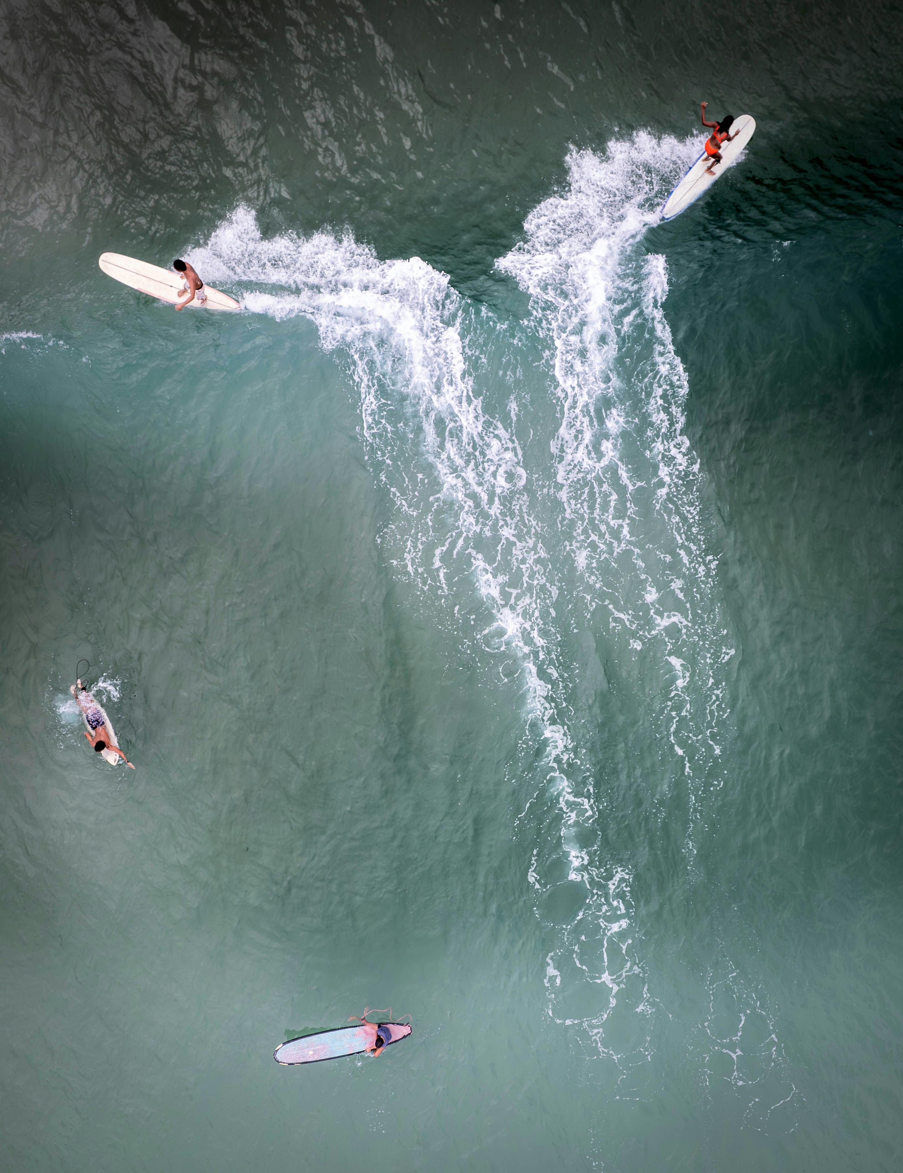 Surfers ride waves on a blue ocean. photo – Free Human Image on Unsplash