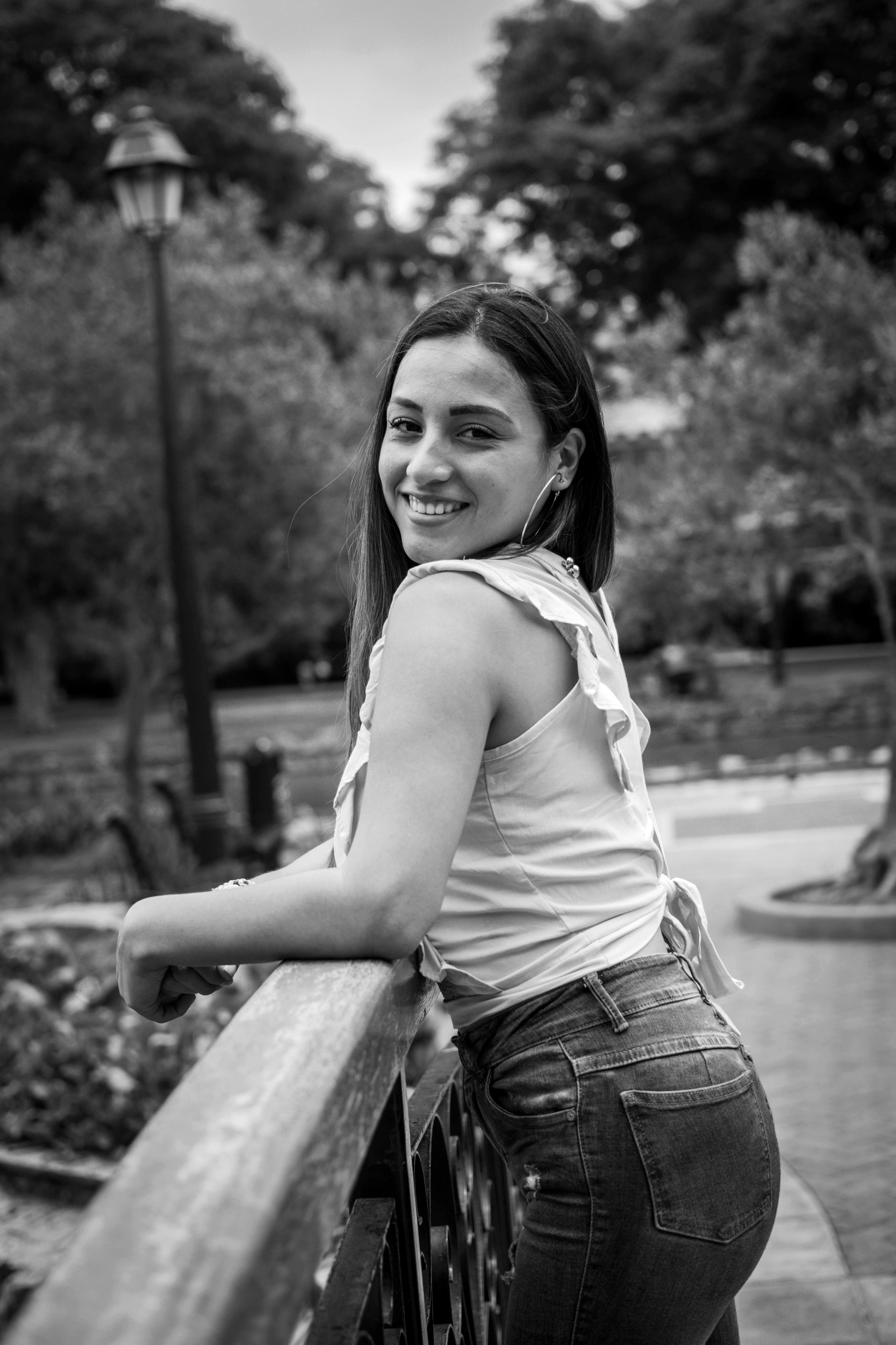 A smiling woman poses by a wooden fence.