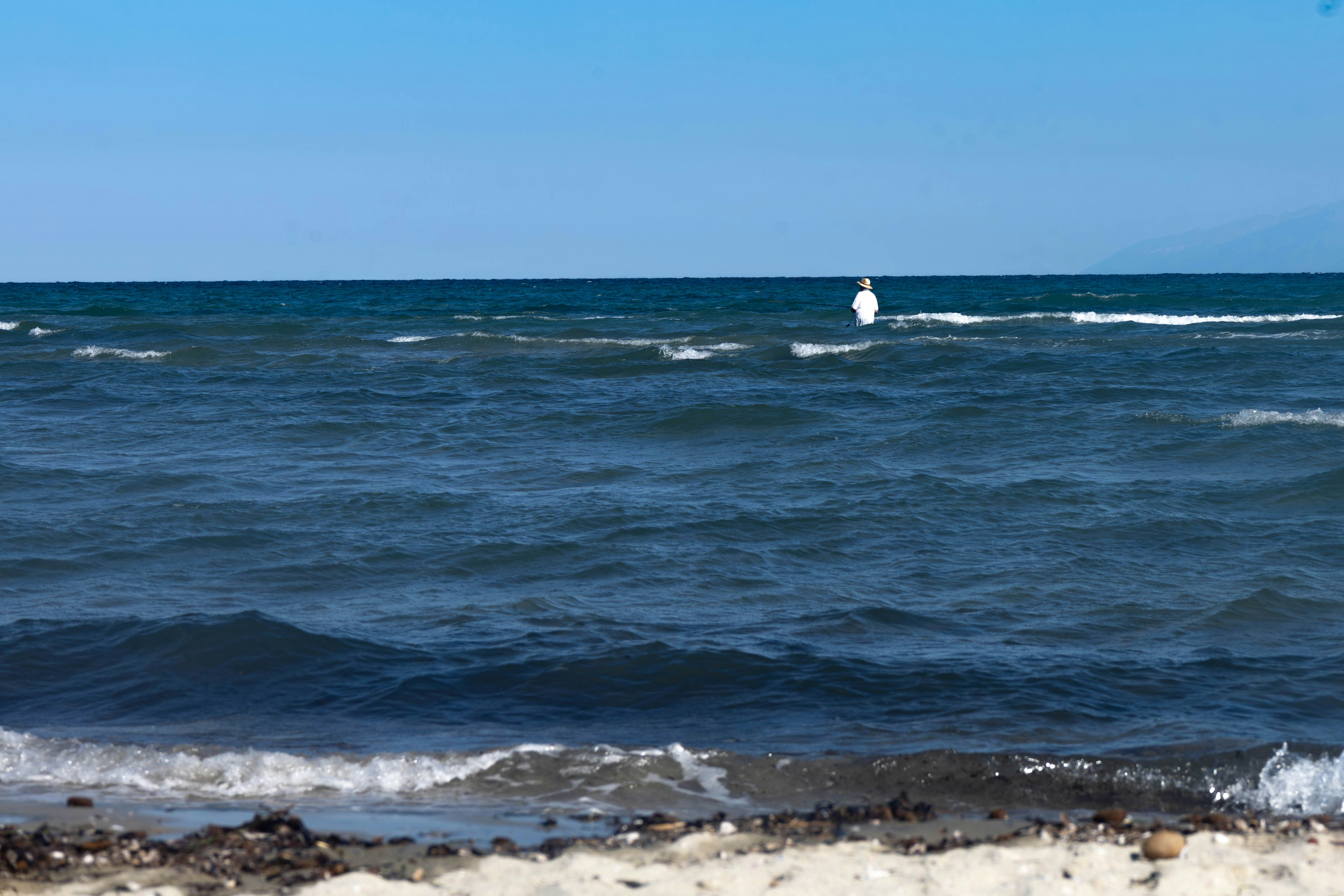 A sailboat navigates the vast blue sea.