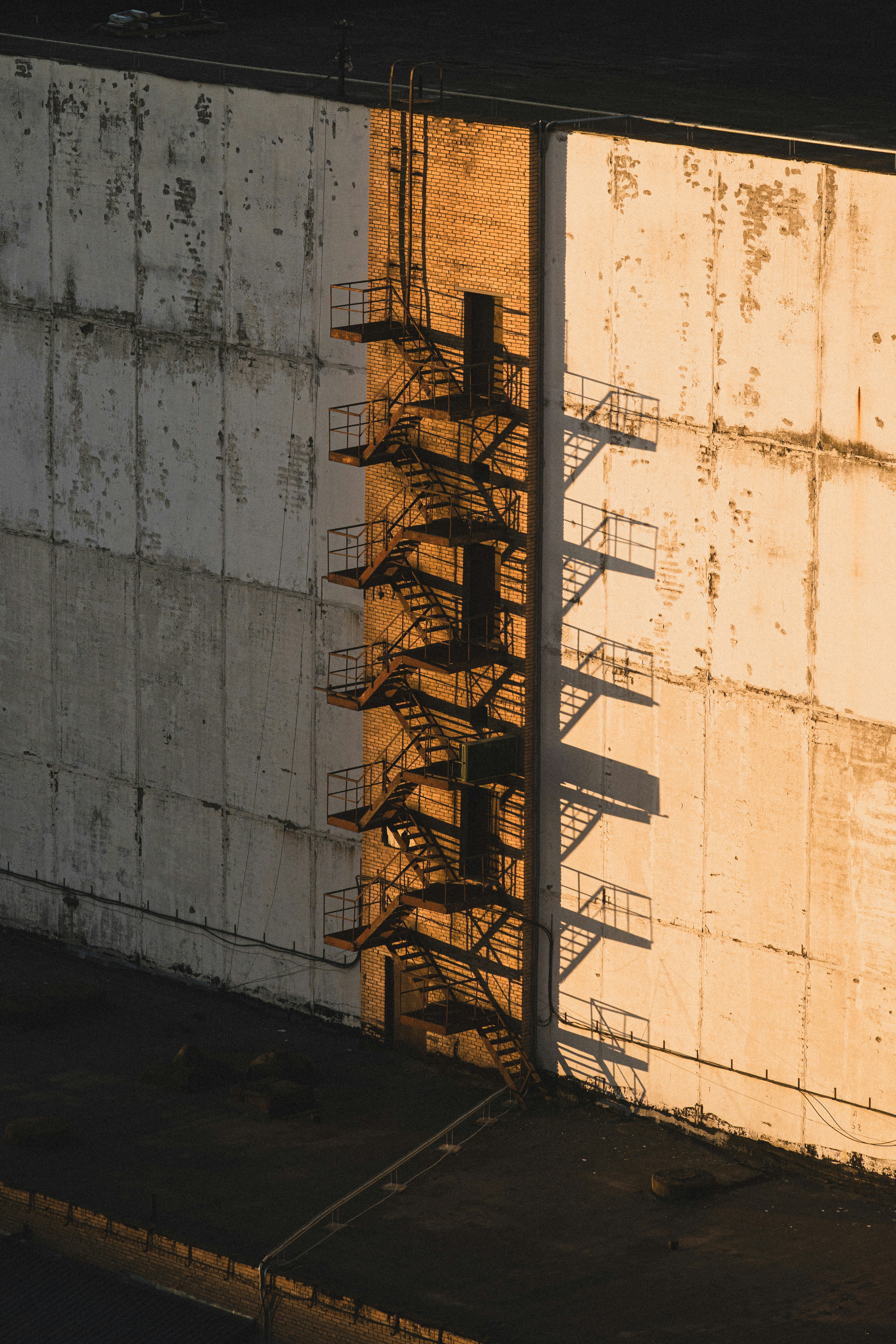 Metal fire escape casts shadows on a concrete wall.
