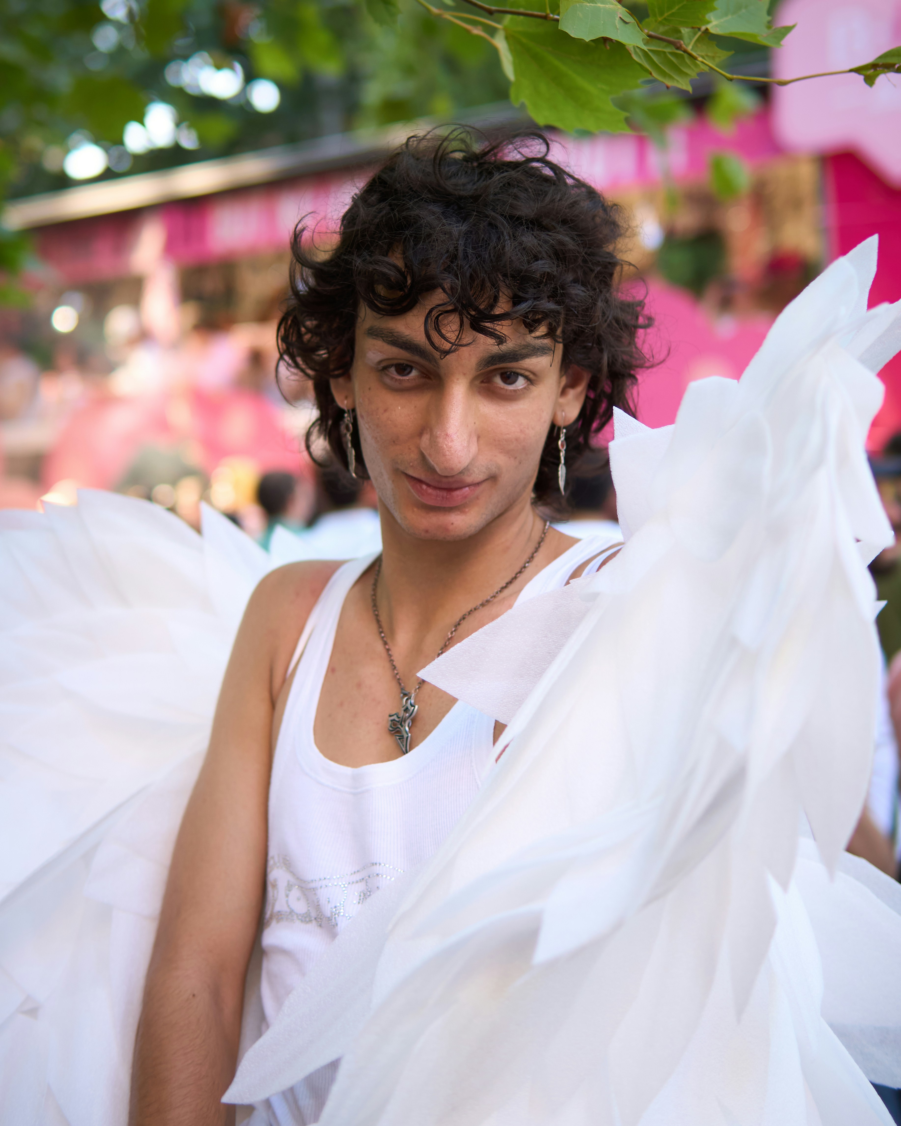 Individual adorned with ethereal white wings, exuding a playful charm amidst a vibrant backdrop. The scene captures a moment of whimsical expression.