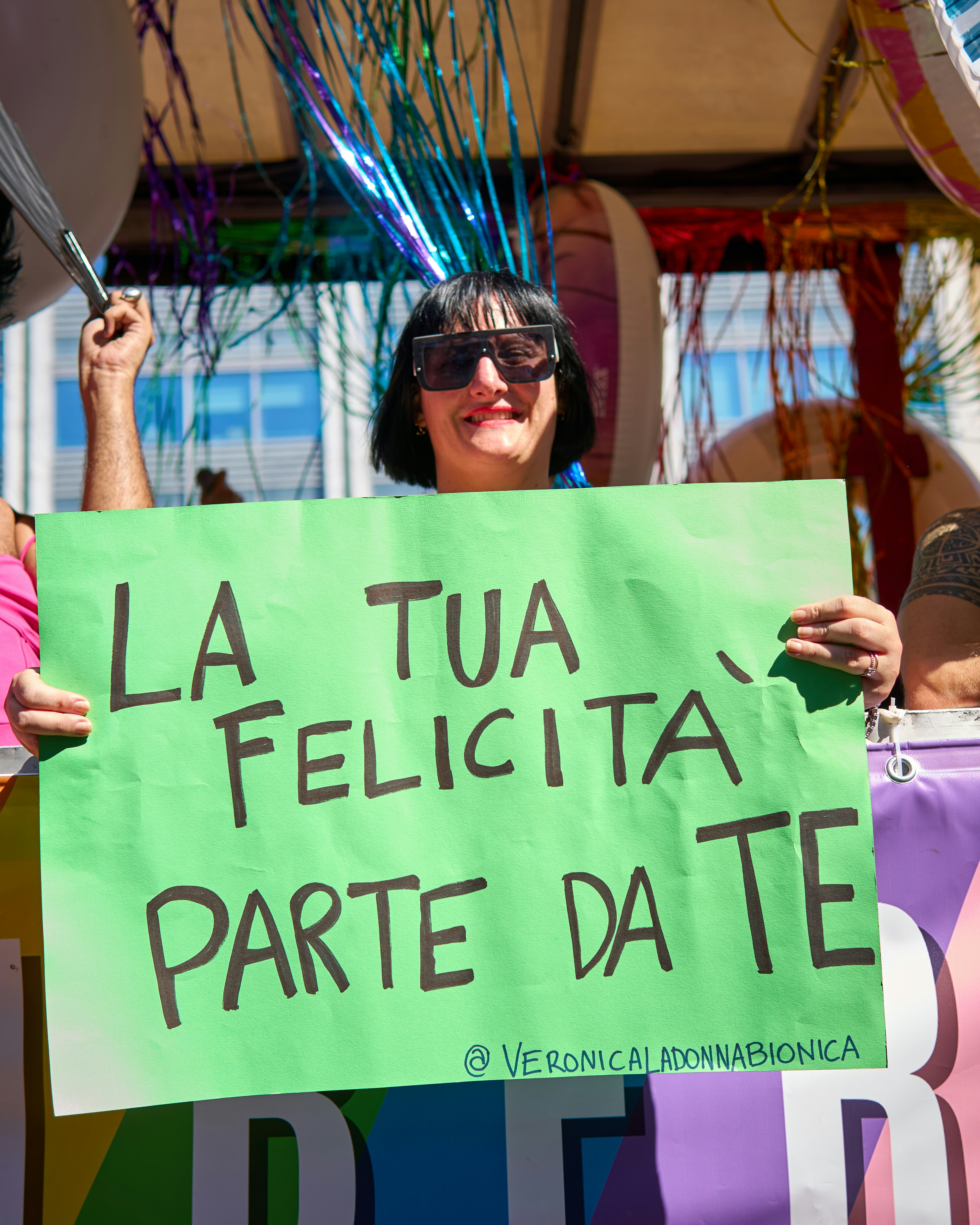La Tua Felicita: Neon Green Sign Anchoring a Colorful Street Celebration
