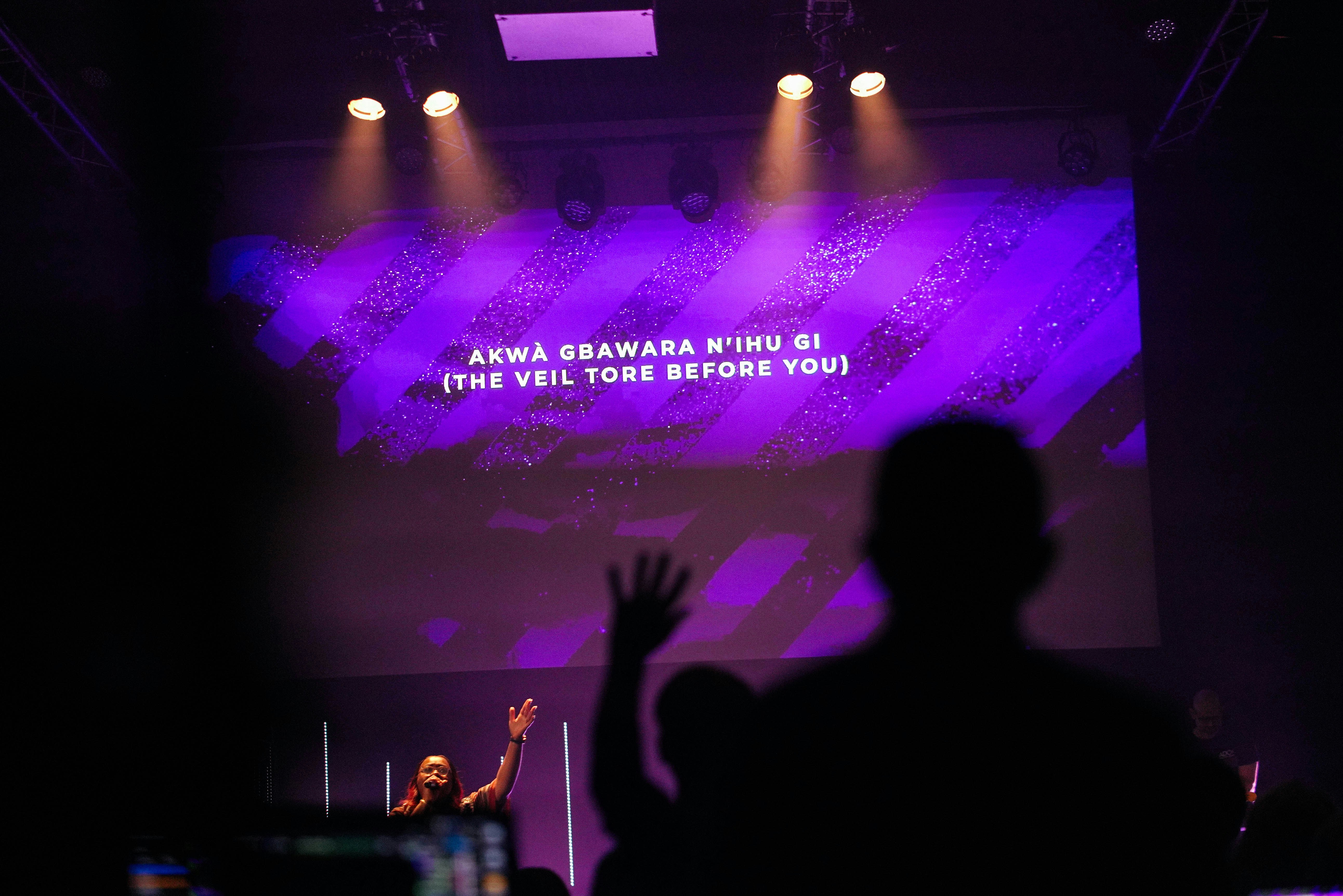 People are watching a stage with purple light.