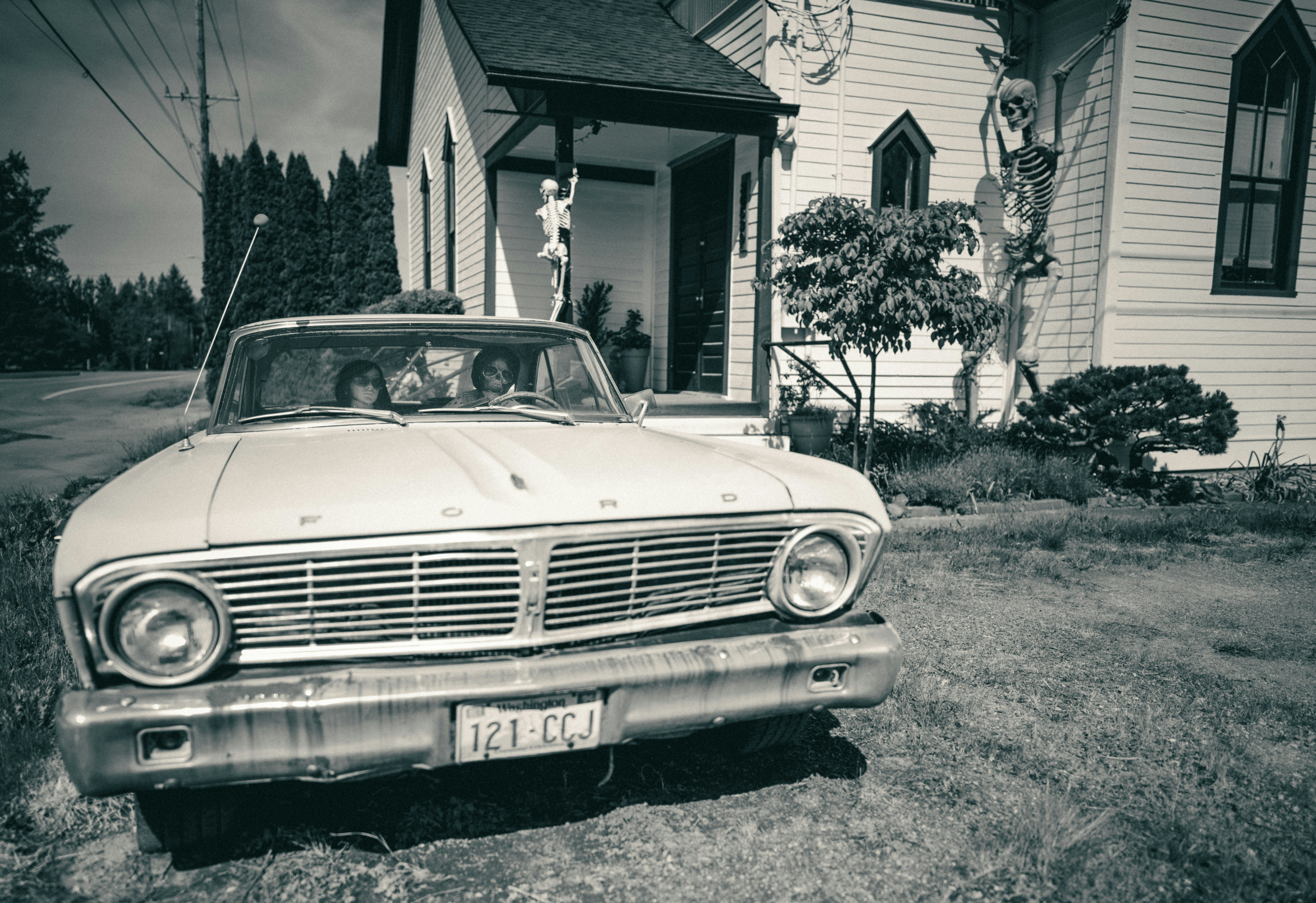 Vintage car parks near a white house.