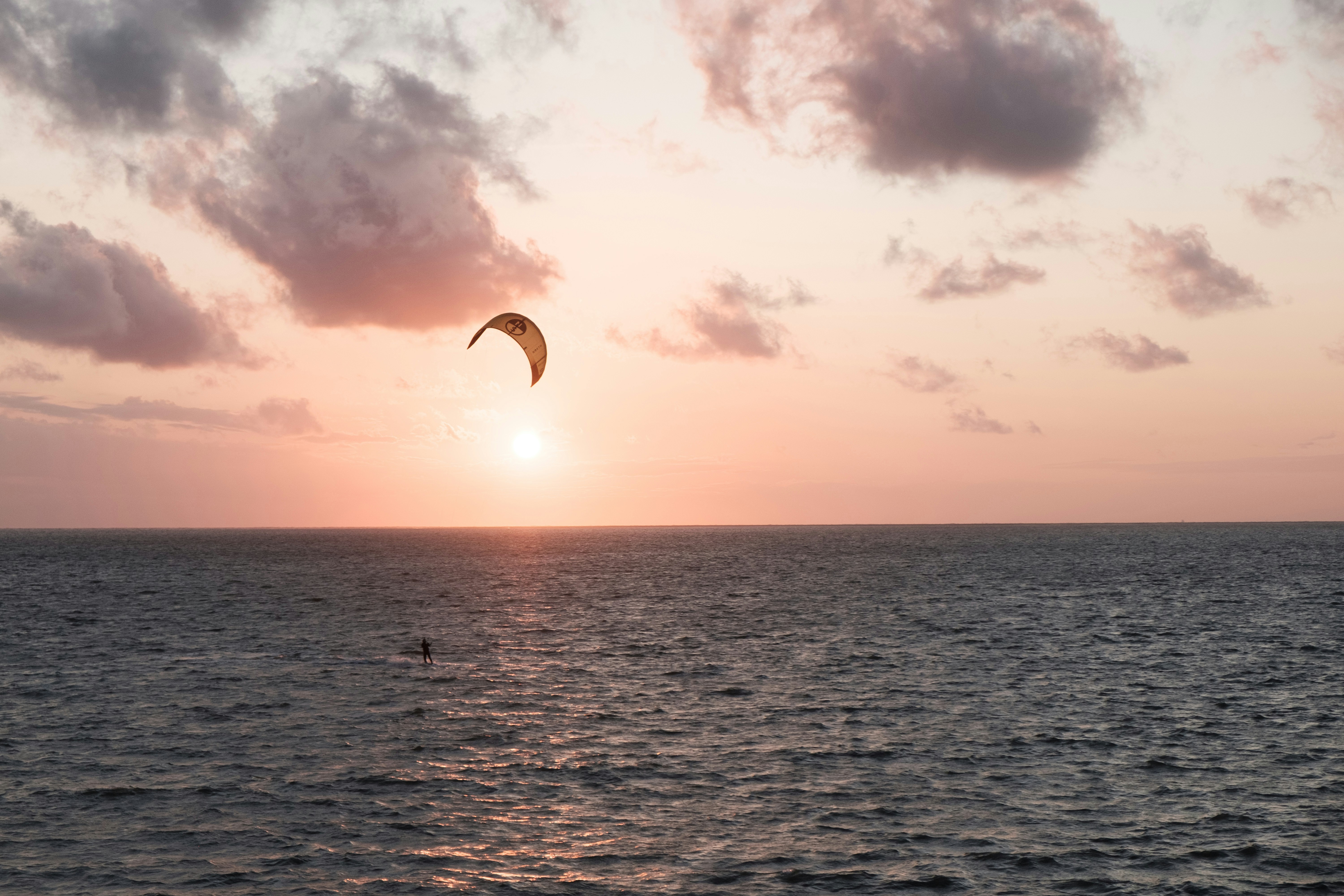Kite surfing at sunset over the ocean.