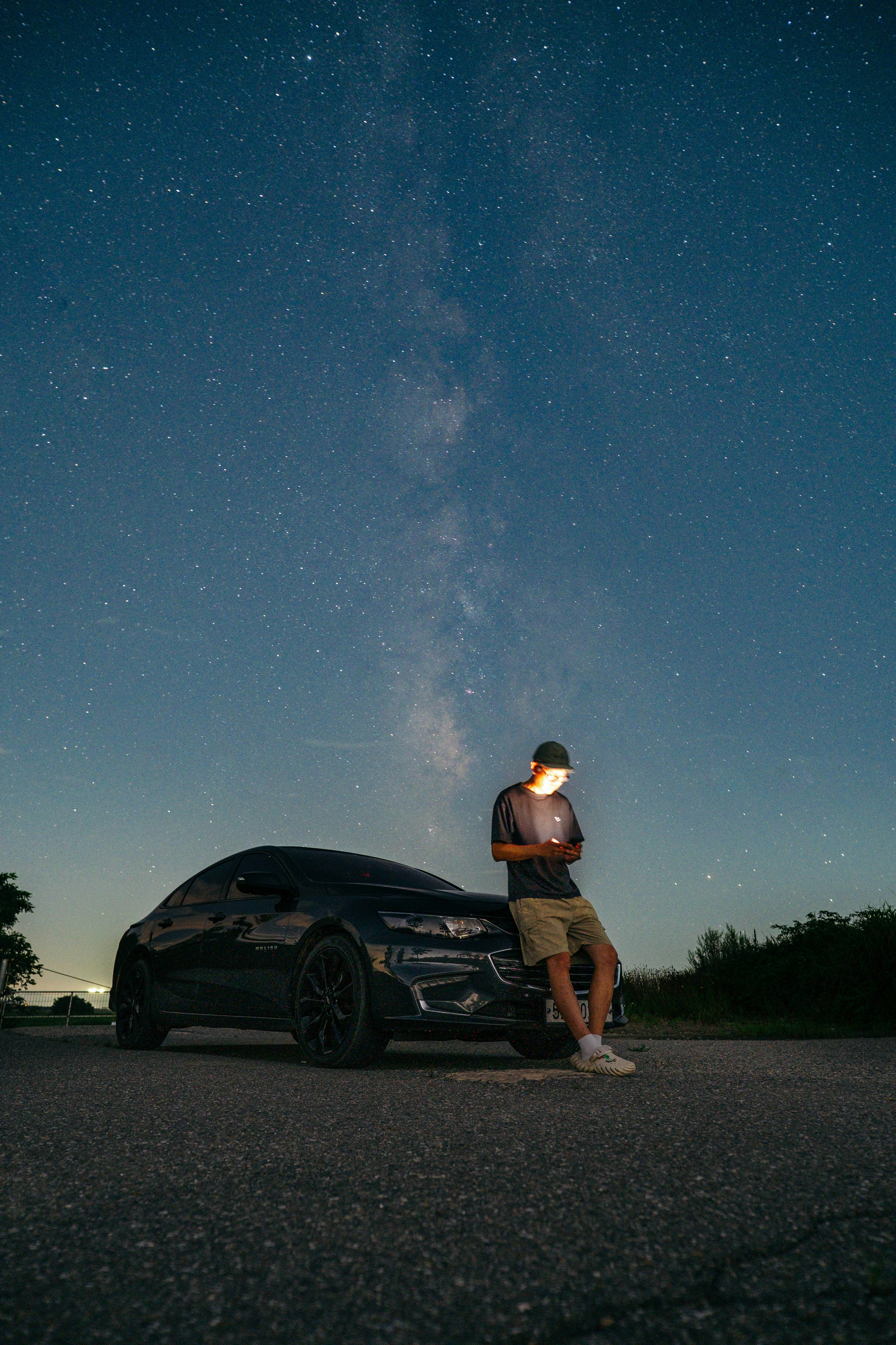 Man next to a car under a starry night sky.
