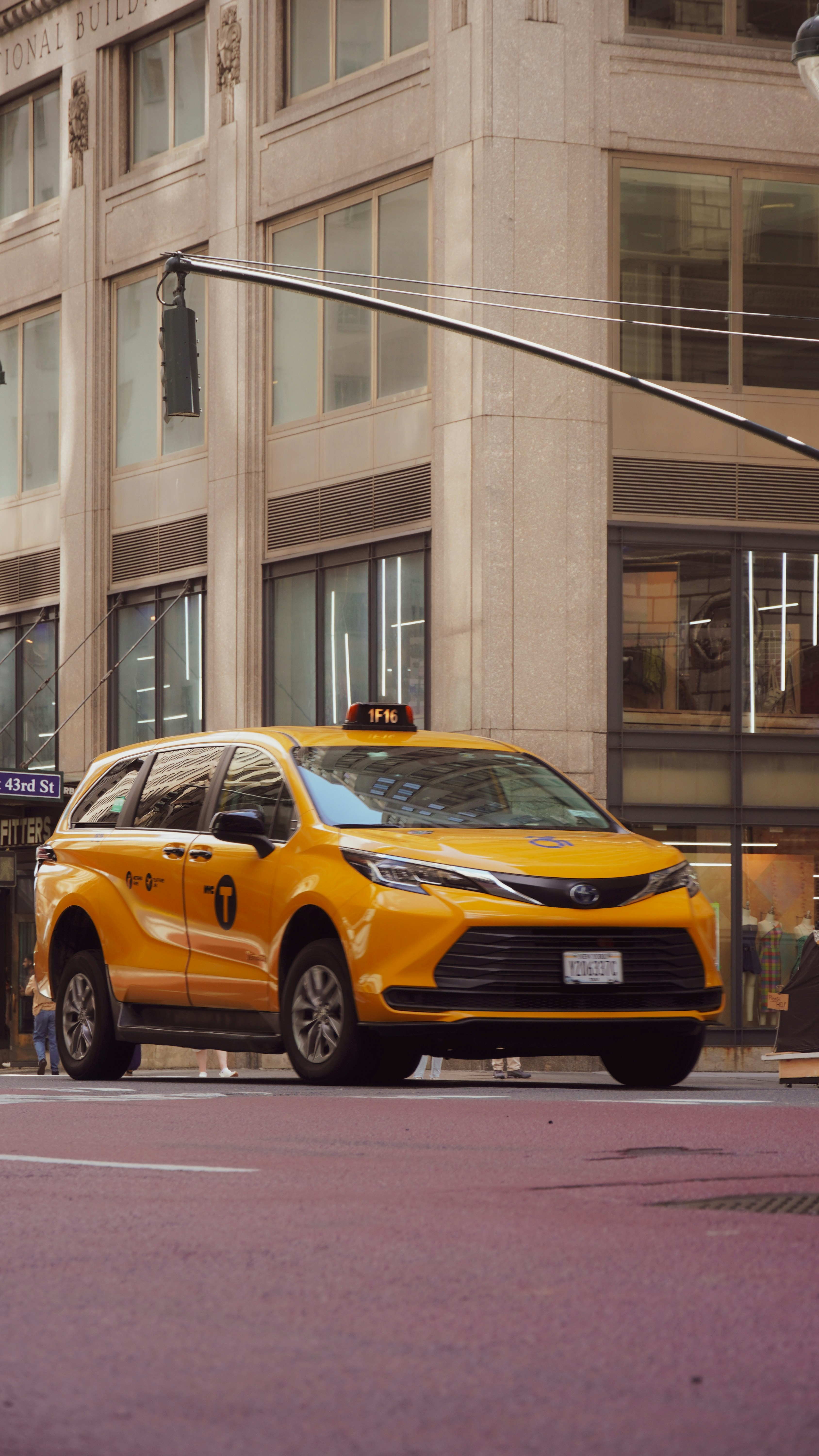 A yellow taxi drives down a city street.