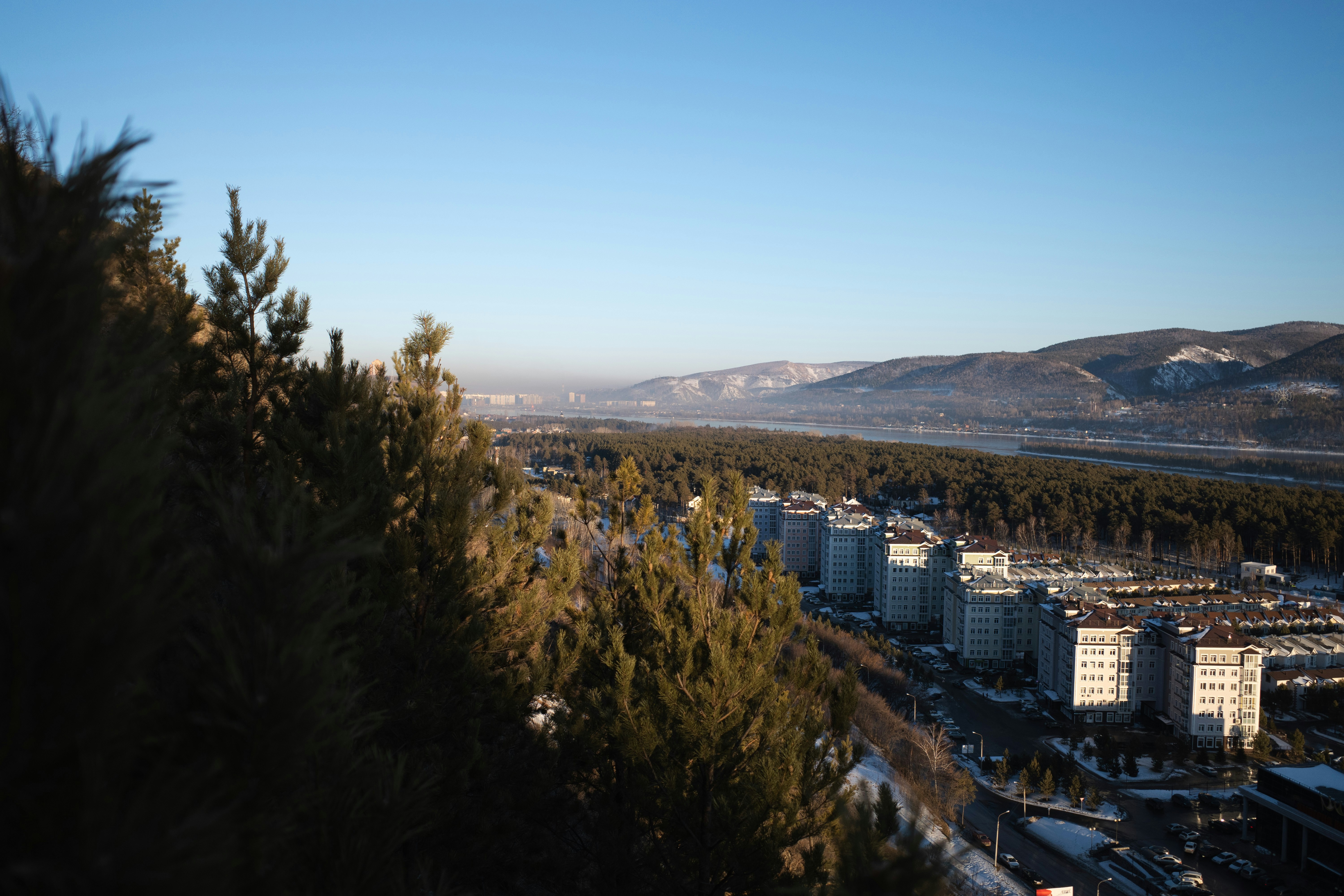 A city is nestled near mountains and trees.