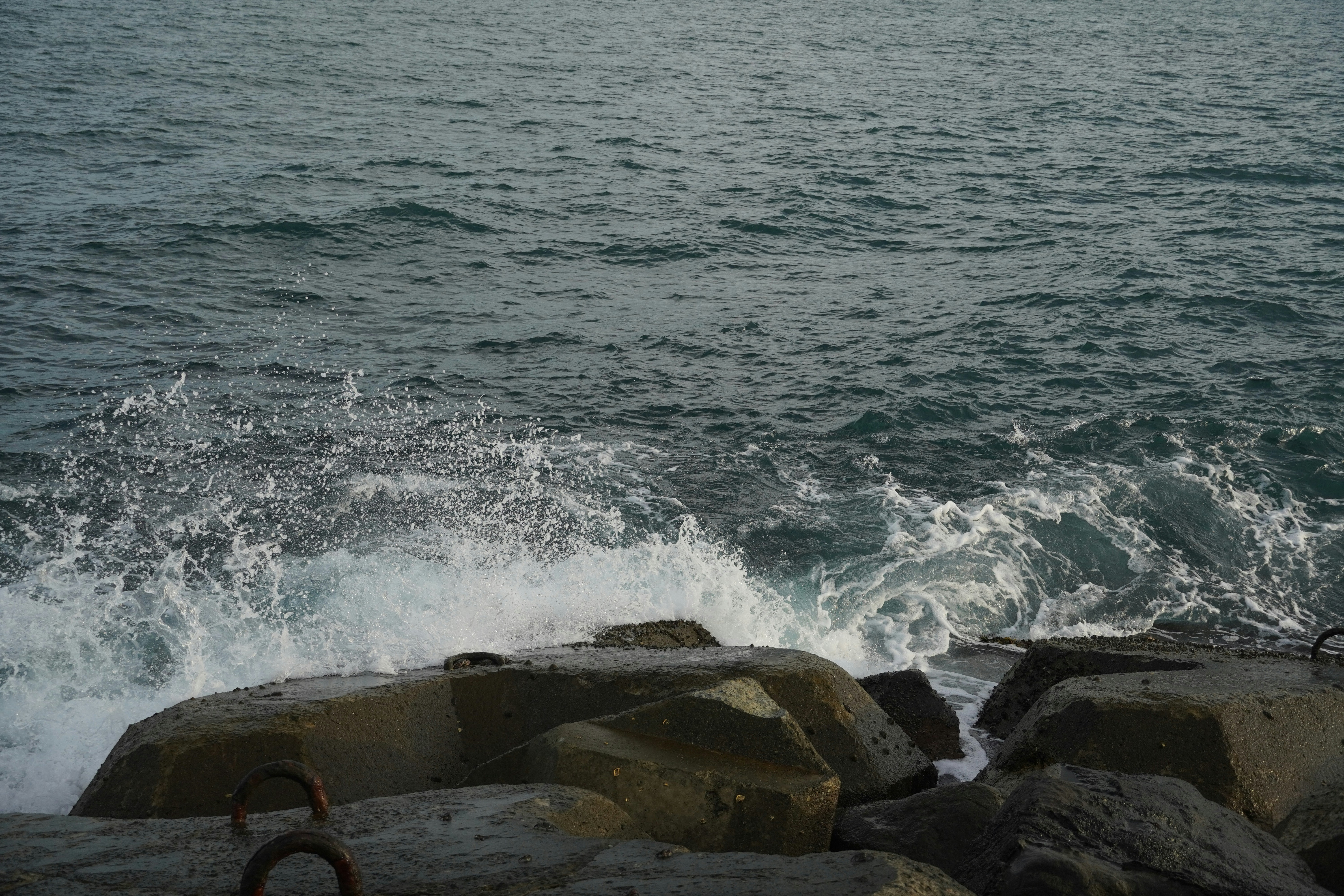Waves crash against rocks at the seashore.