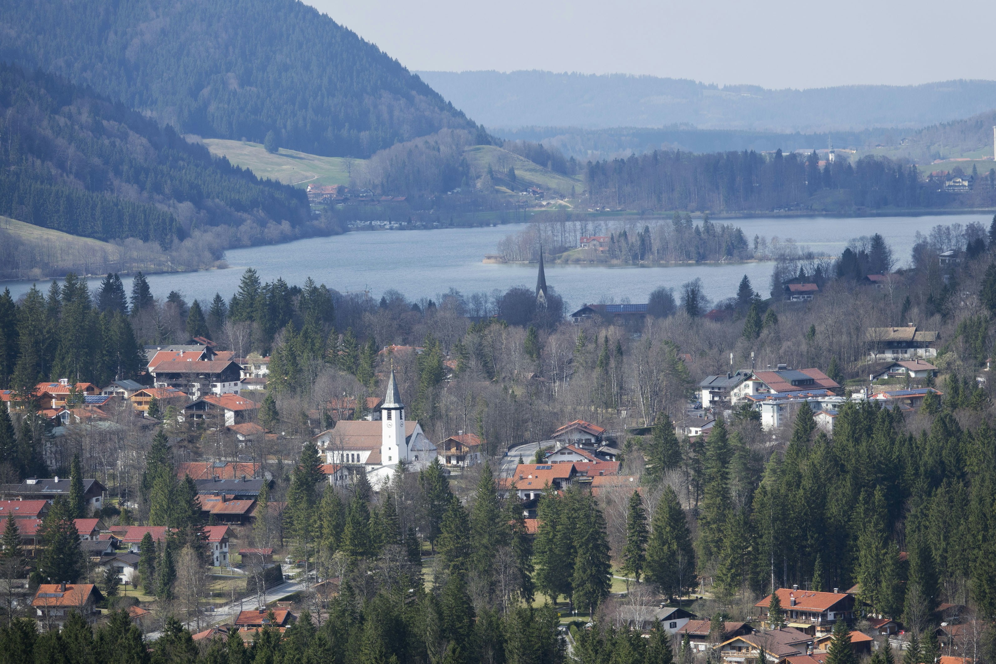 A village nestled by a lake and mountains.