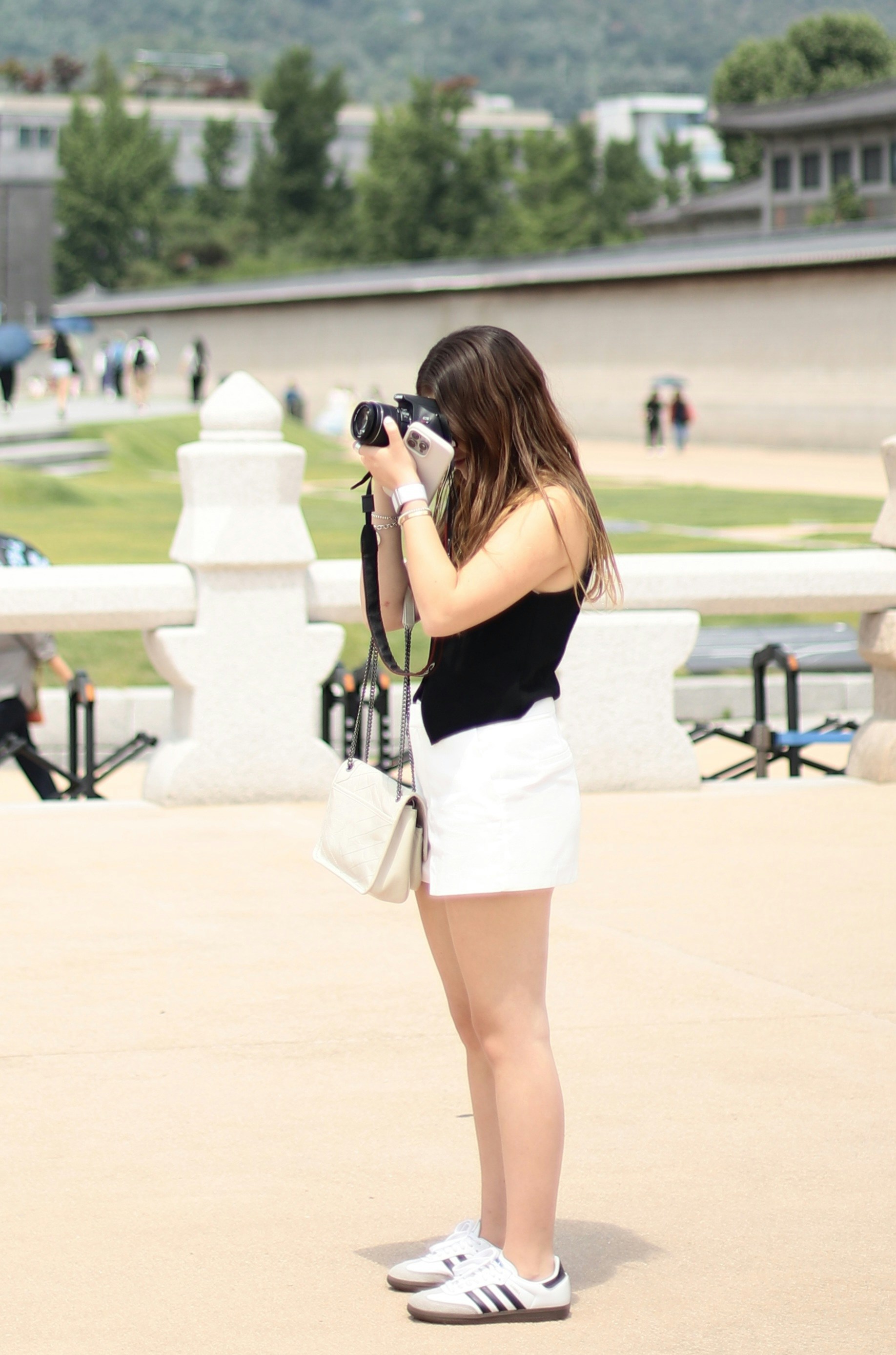 A young woman stands poised with her camera, ready to capture the world around her. The scene reflects a blend of creativity and exploration.