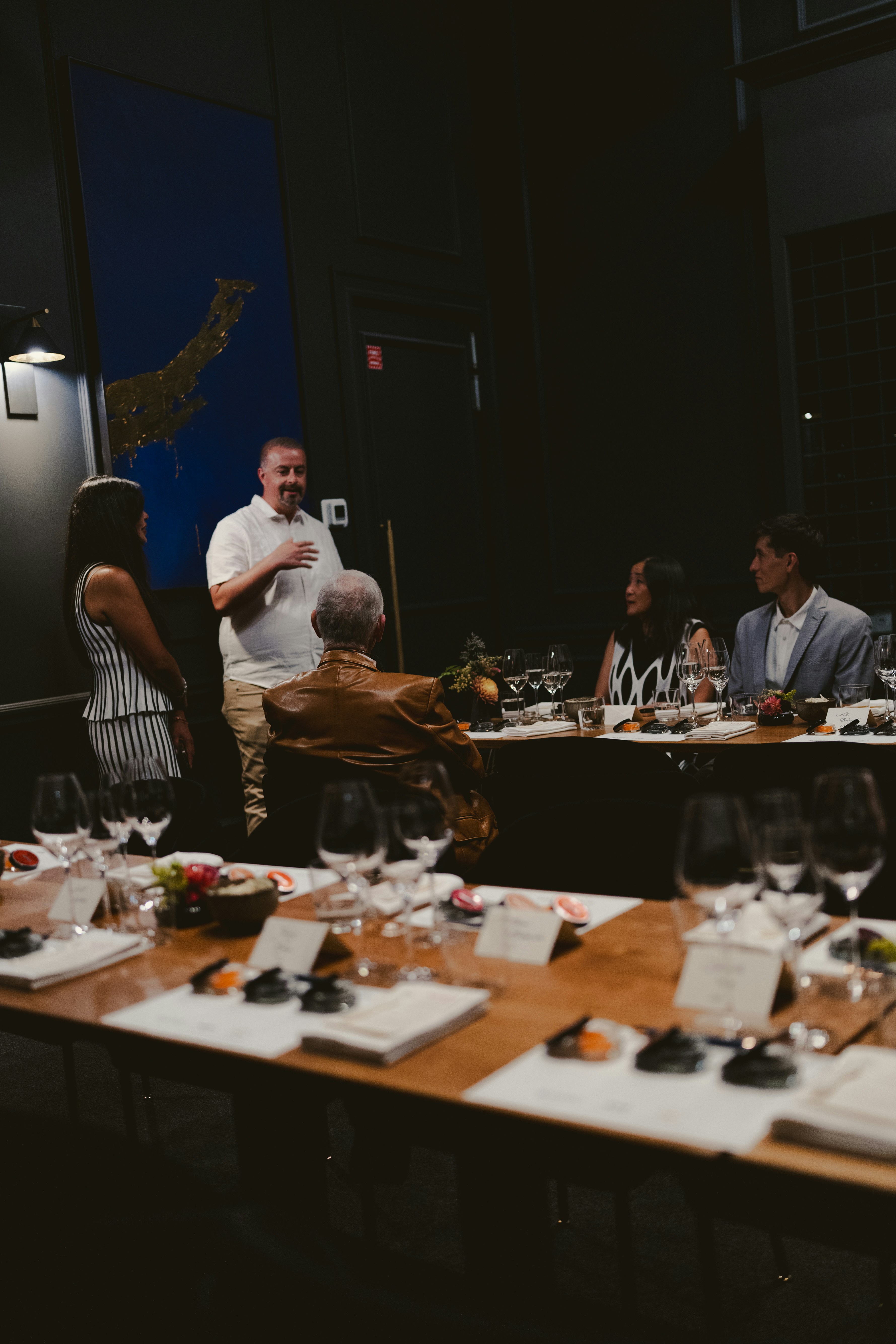 Toasting at a Dimly Lit Dinner: Warm Moments Around a Long Table