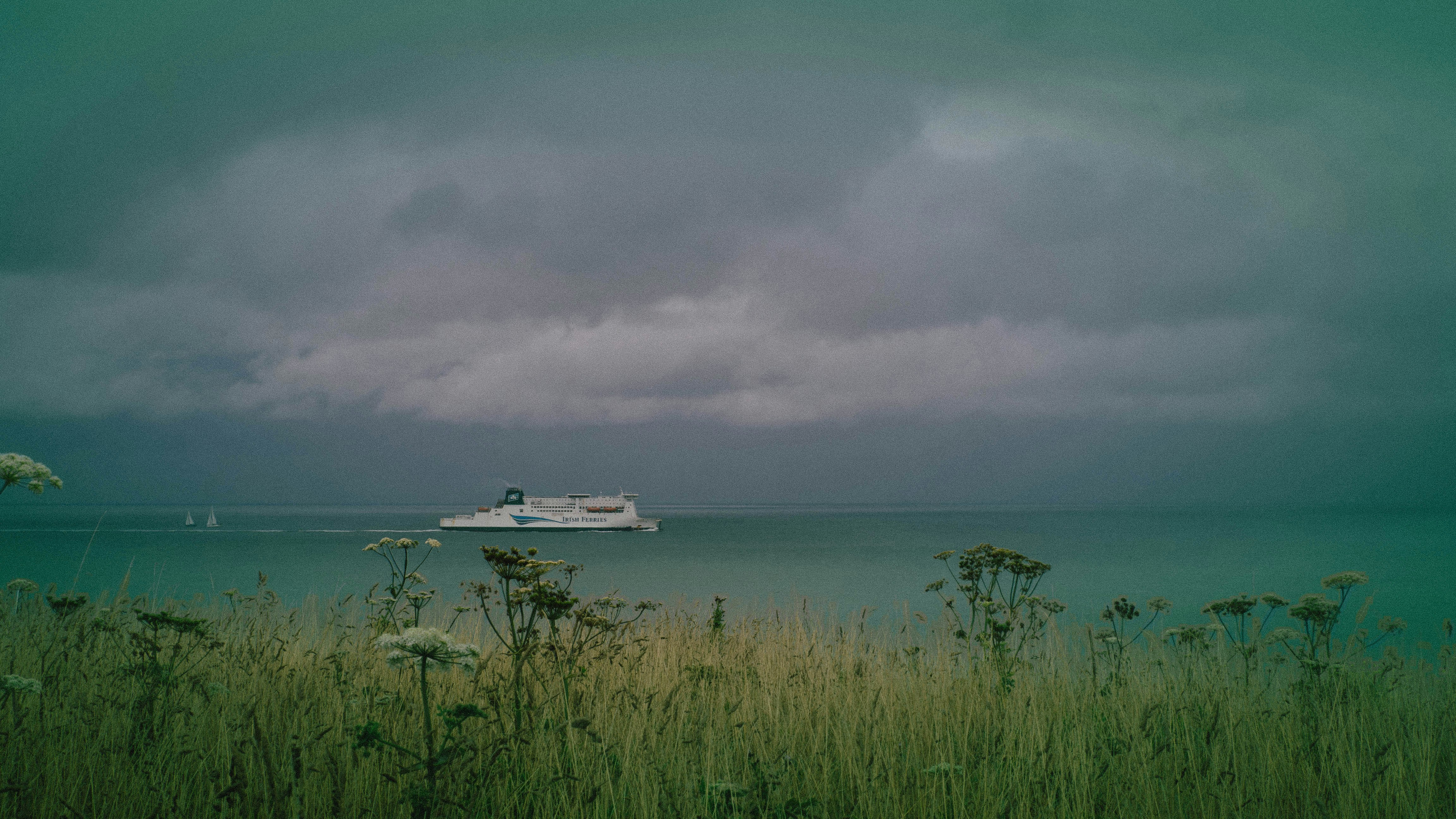 OLYMPUS DIGITAL CAMERA | A ferry sails across the ocean under stormy skies.