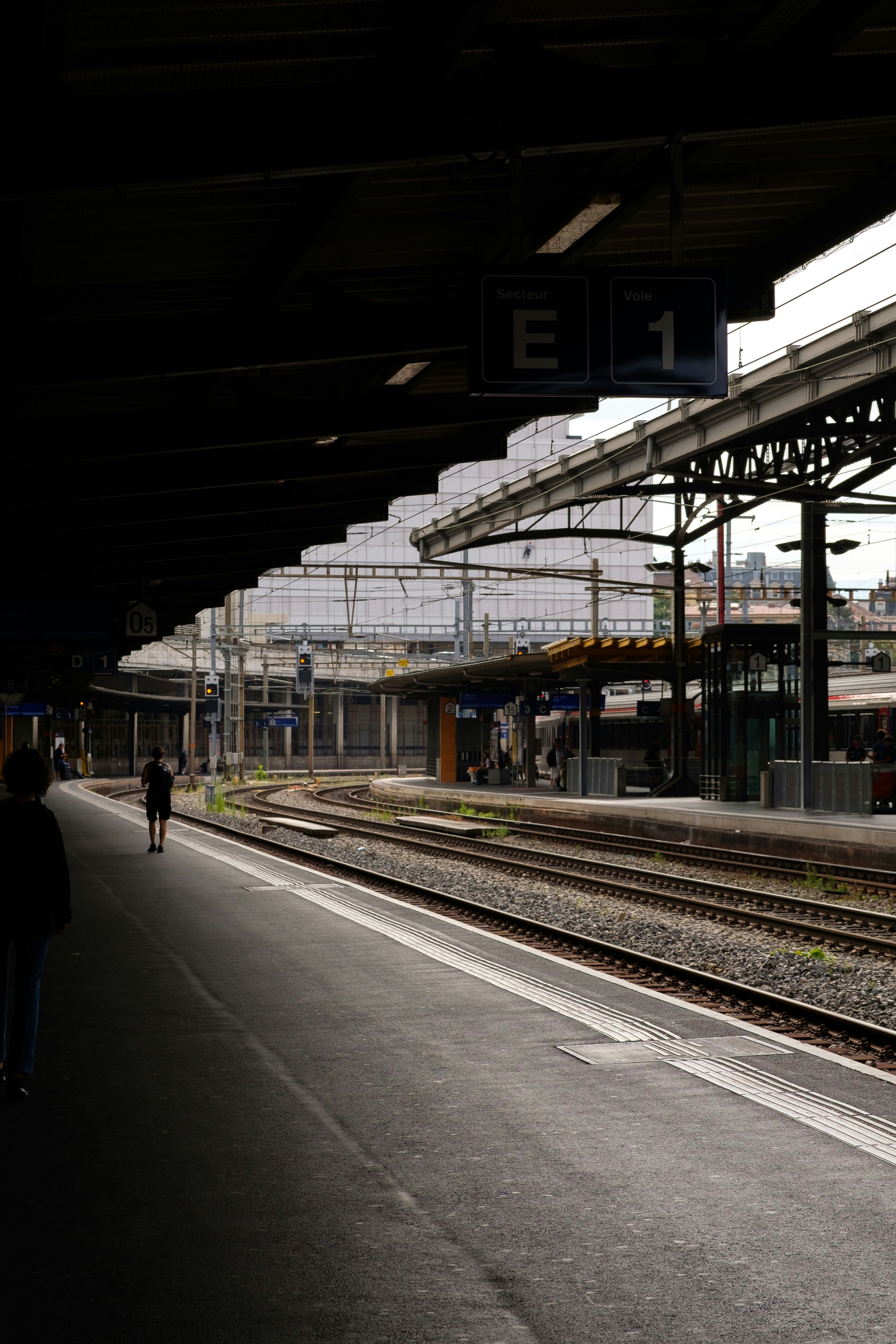 Gare de Lausanne | A train station platform with a person walking.