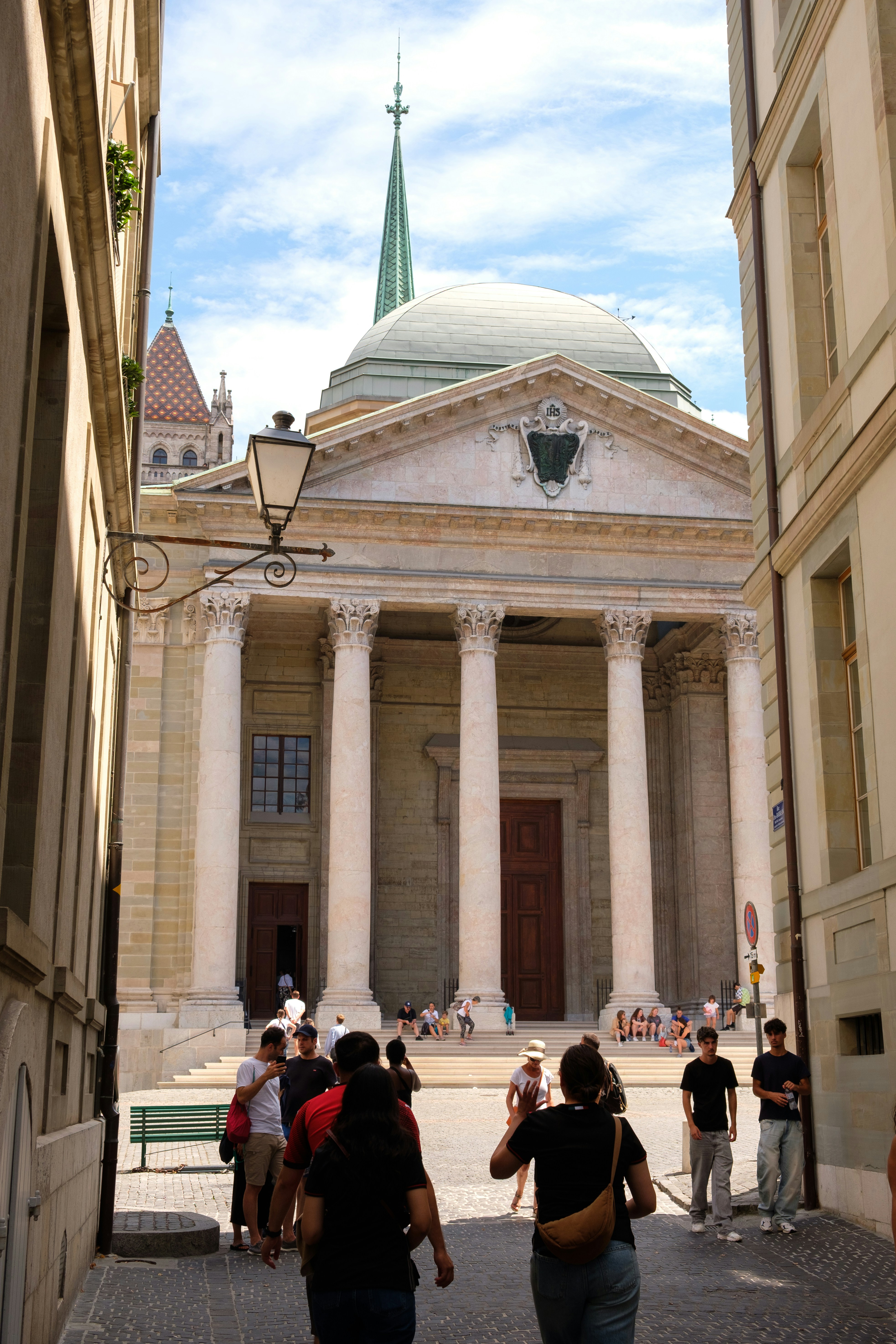 People walk towards a grand building with pillars.