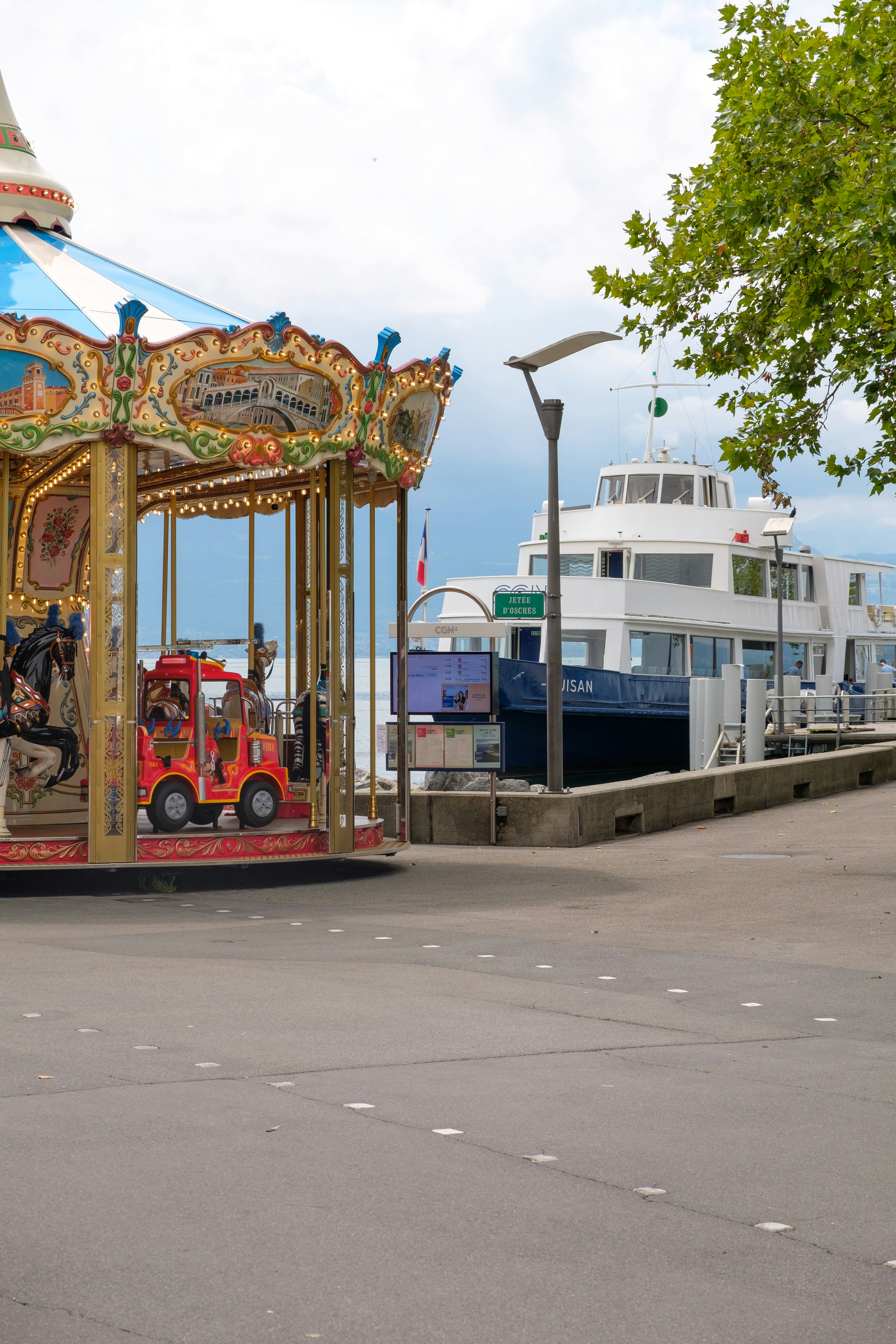A carousel and boat sit near the water. photo – Free Travel Image on ...