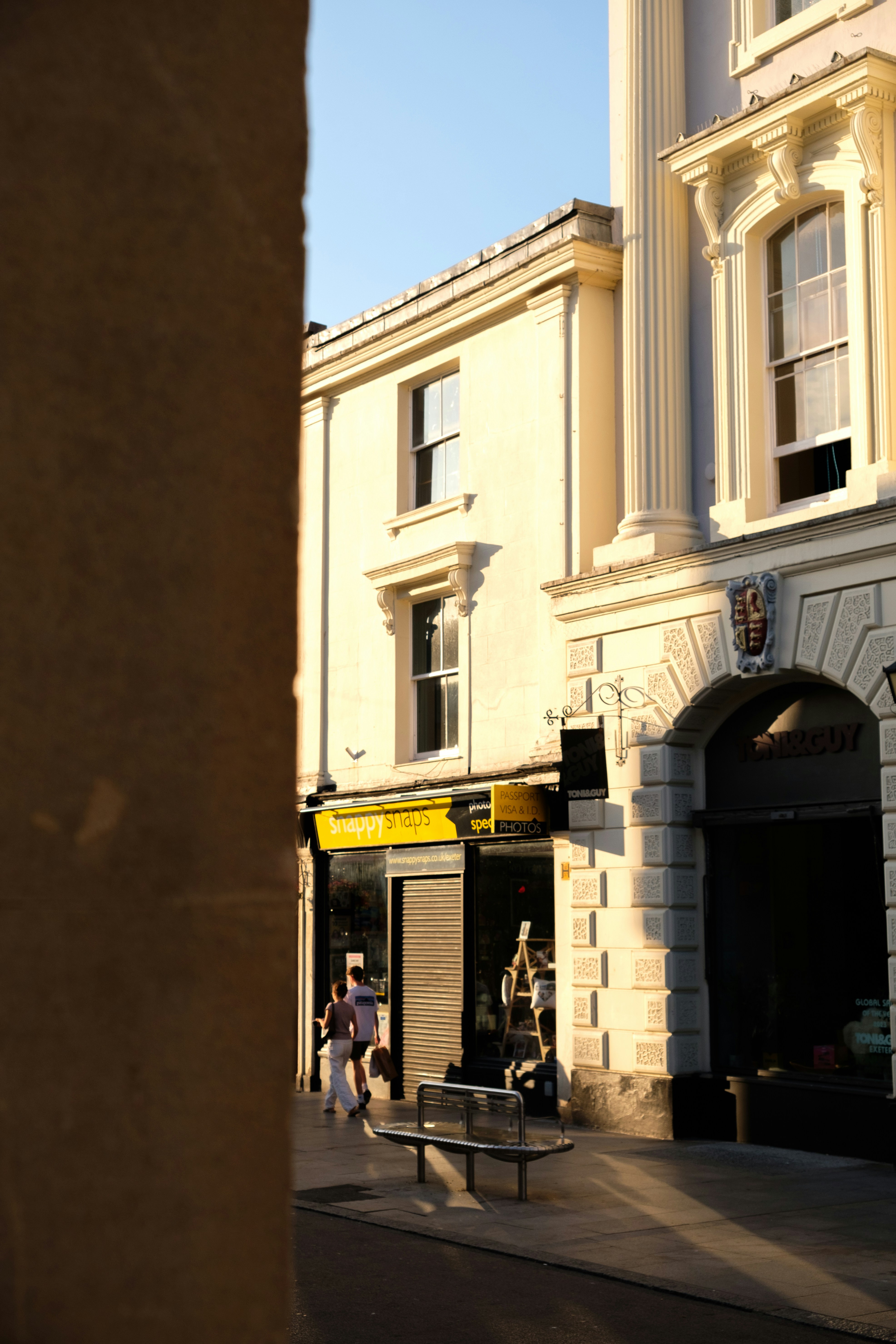 Buildings and shops line a sunny street.