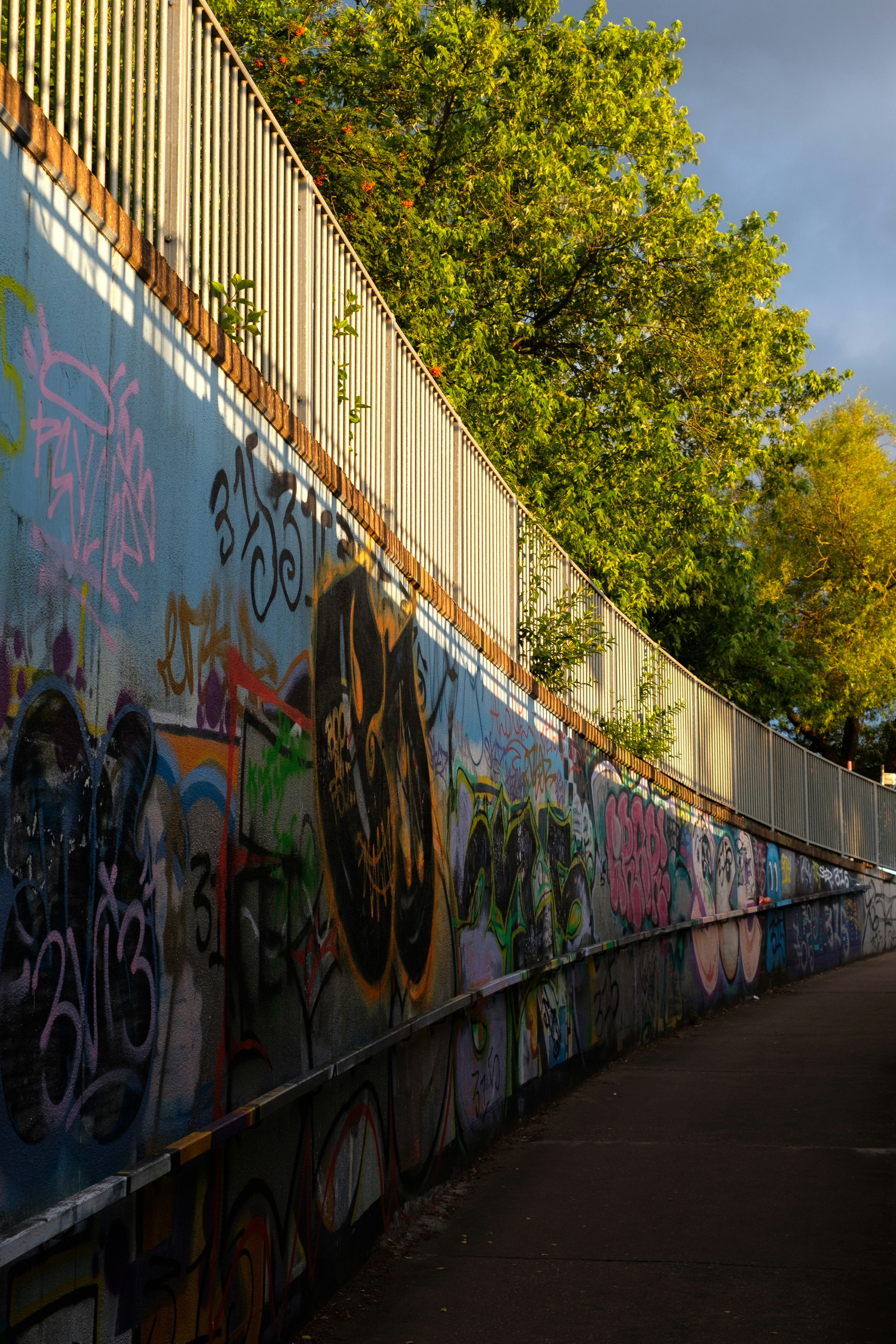 Graffiti covers a curving wall with a railing.