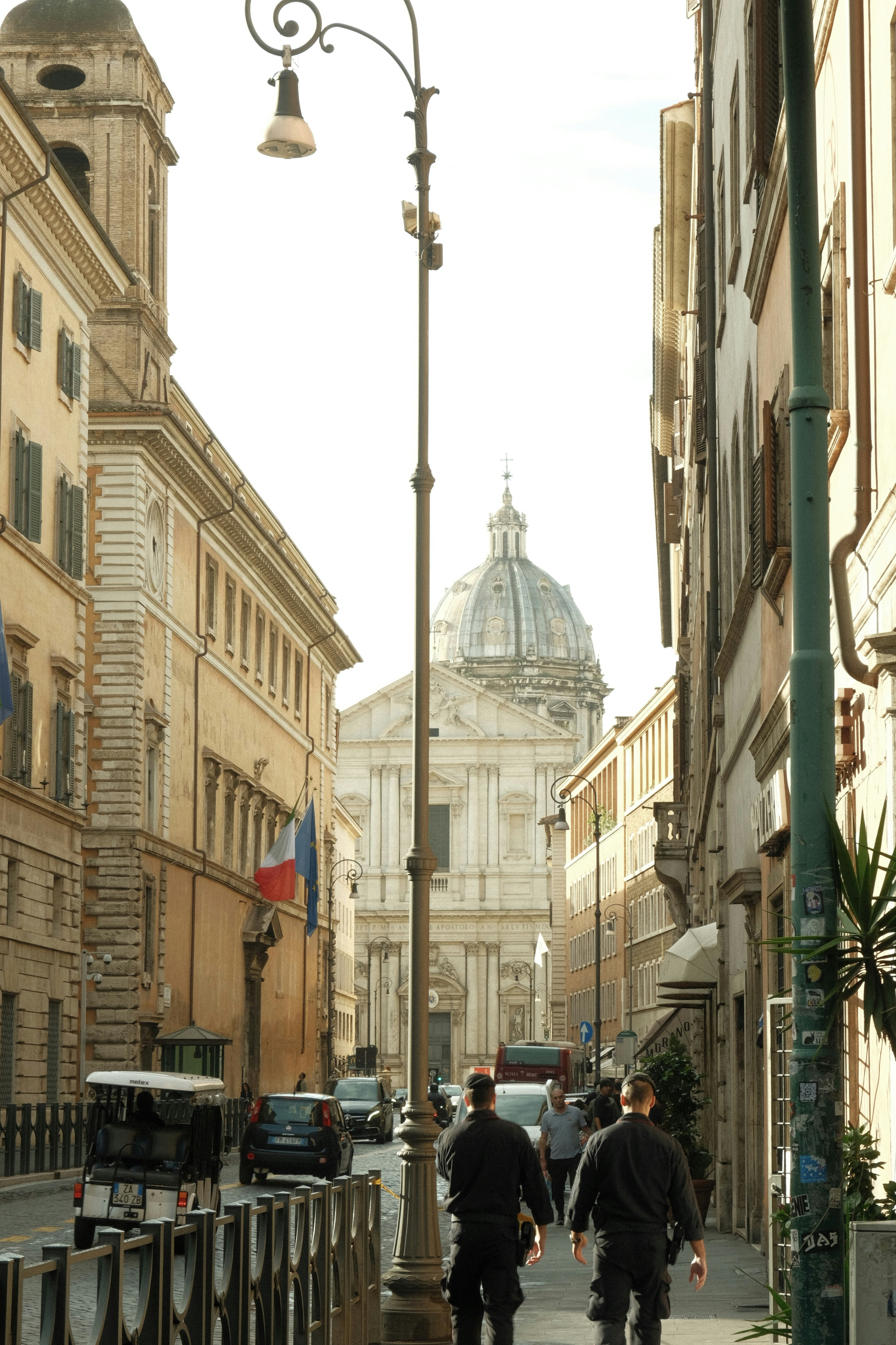 A narrow italian street with a church in the distance.