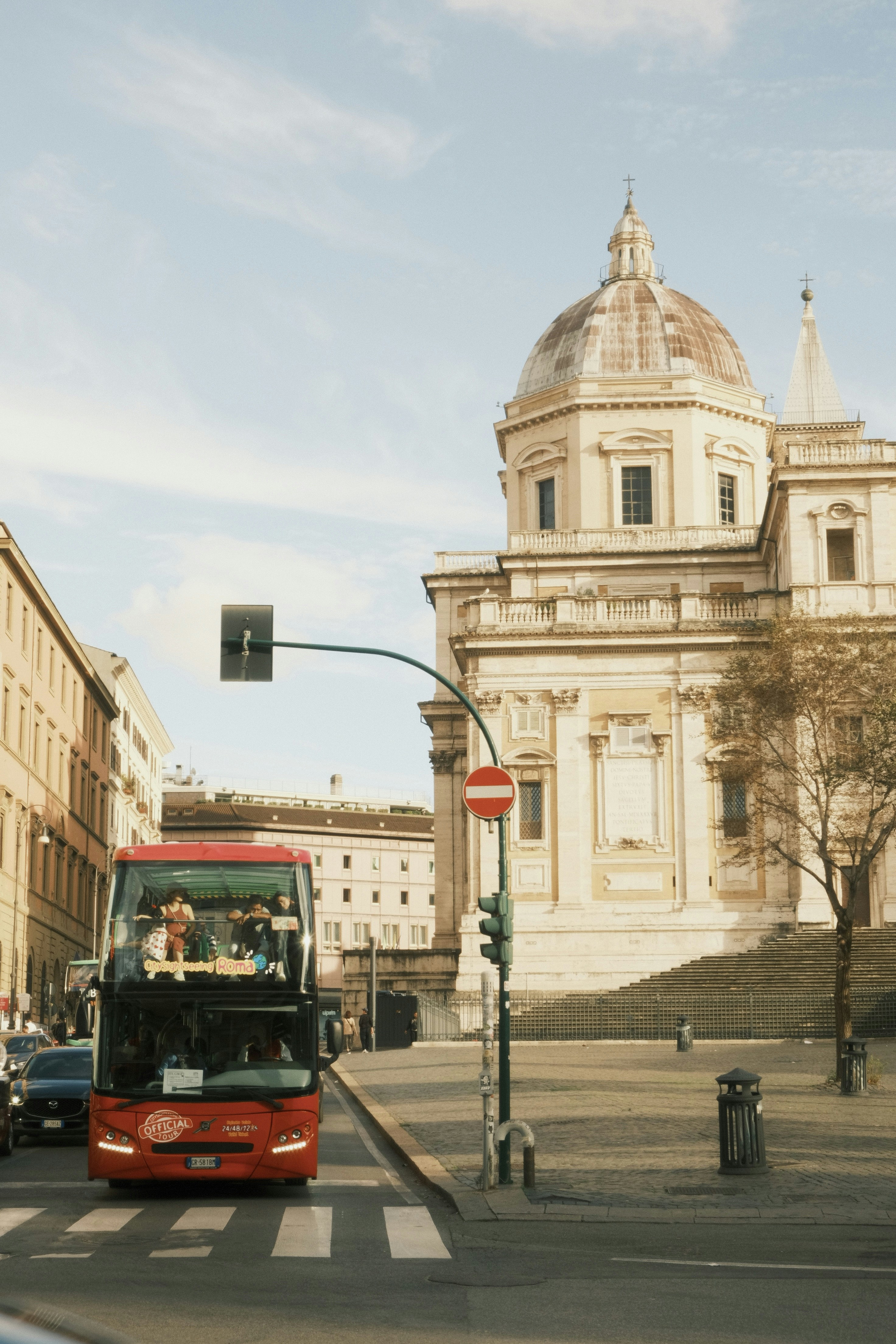A double-decker bus drives past a church.