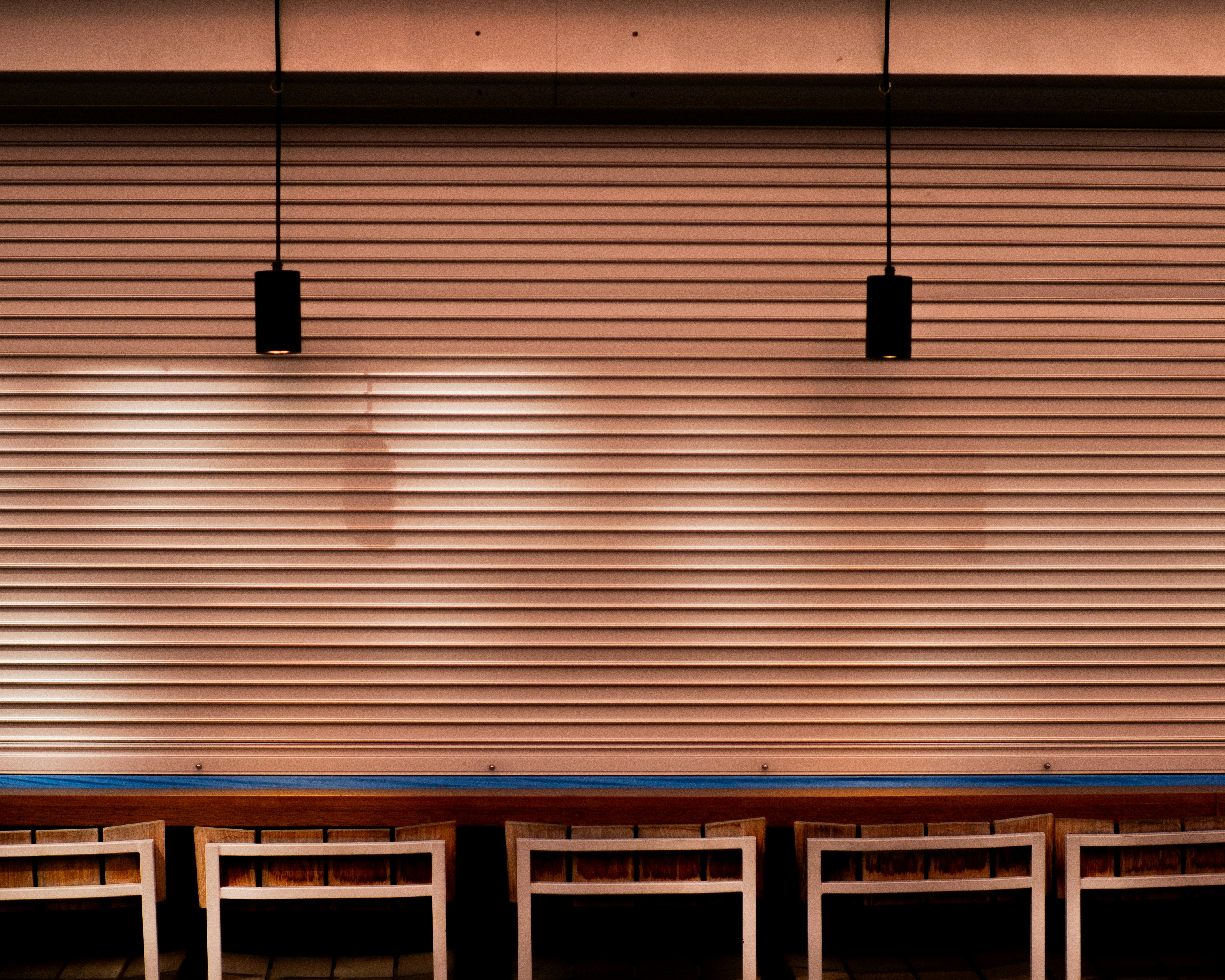 Muted Neon Silence: Row of Benches Before a Rusty Shutter
