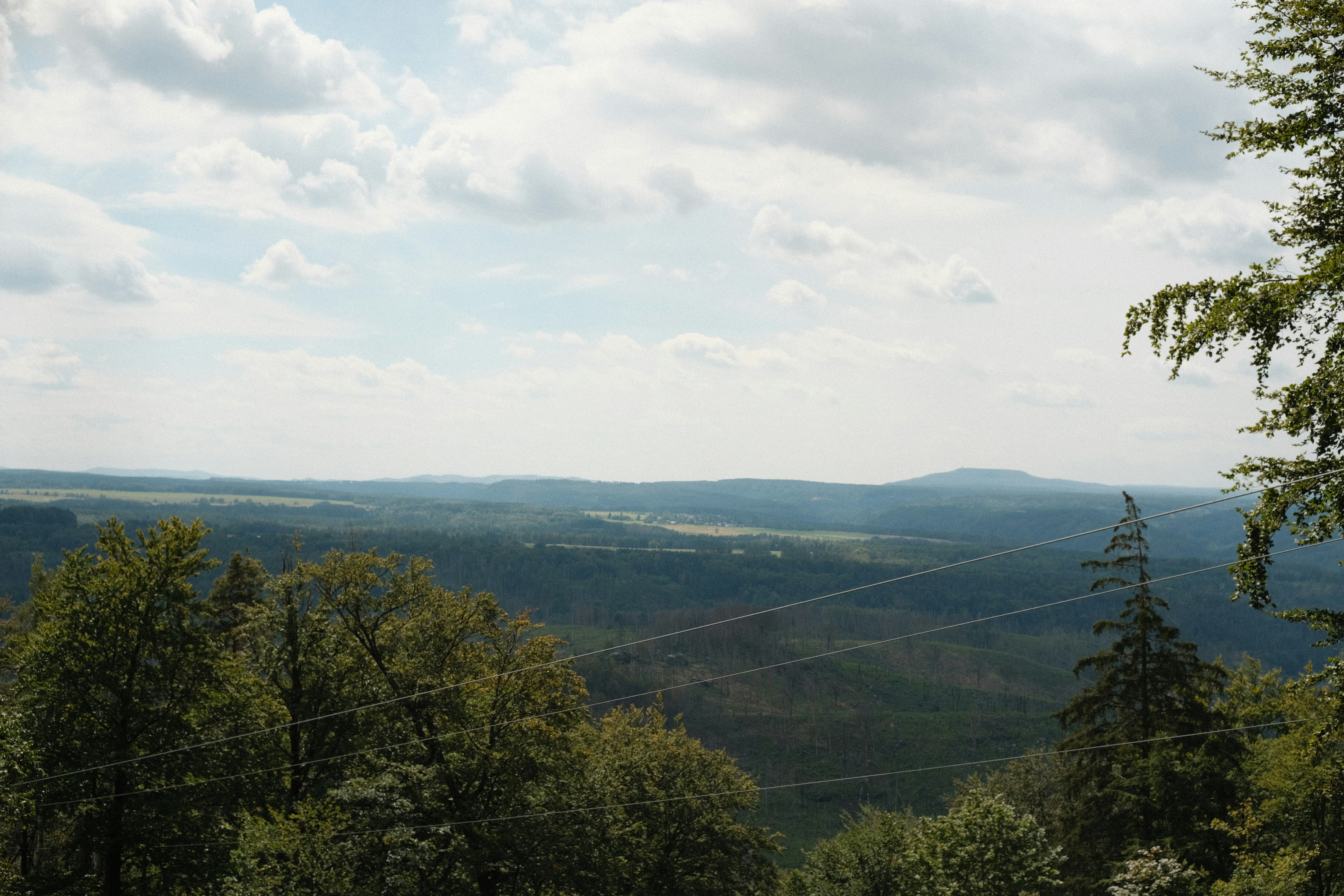 Hills and trees under a cloudy sky.
